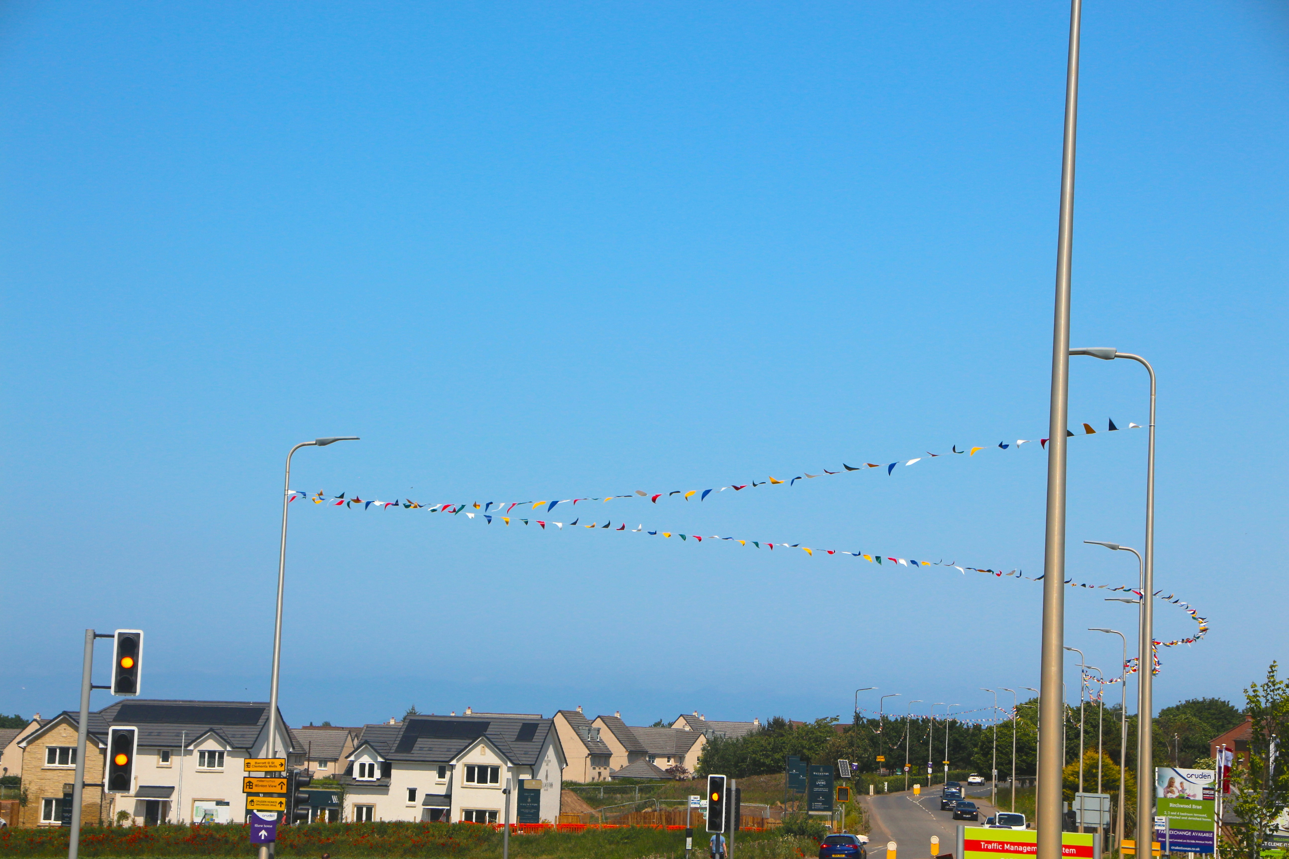 Colorful bunting drapes a bright midday over a quiet suburban crossroads