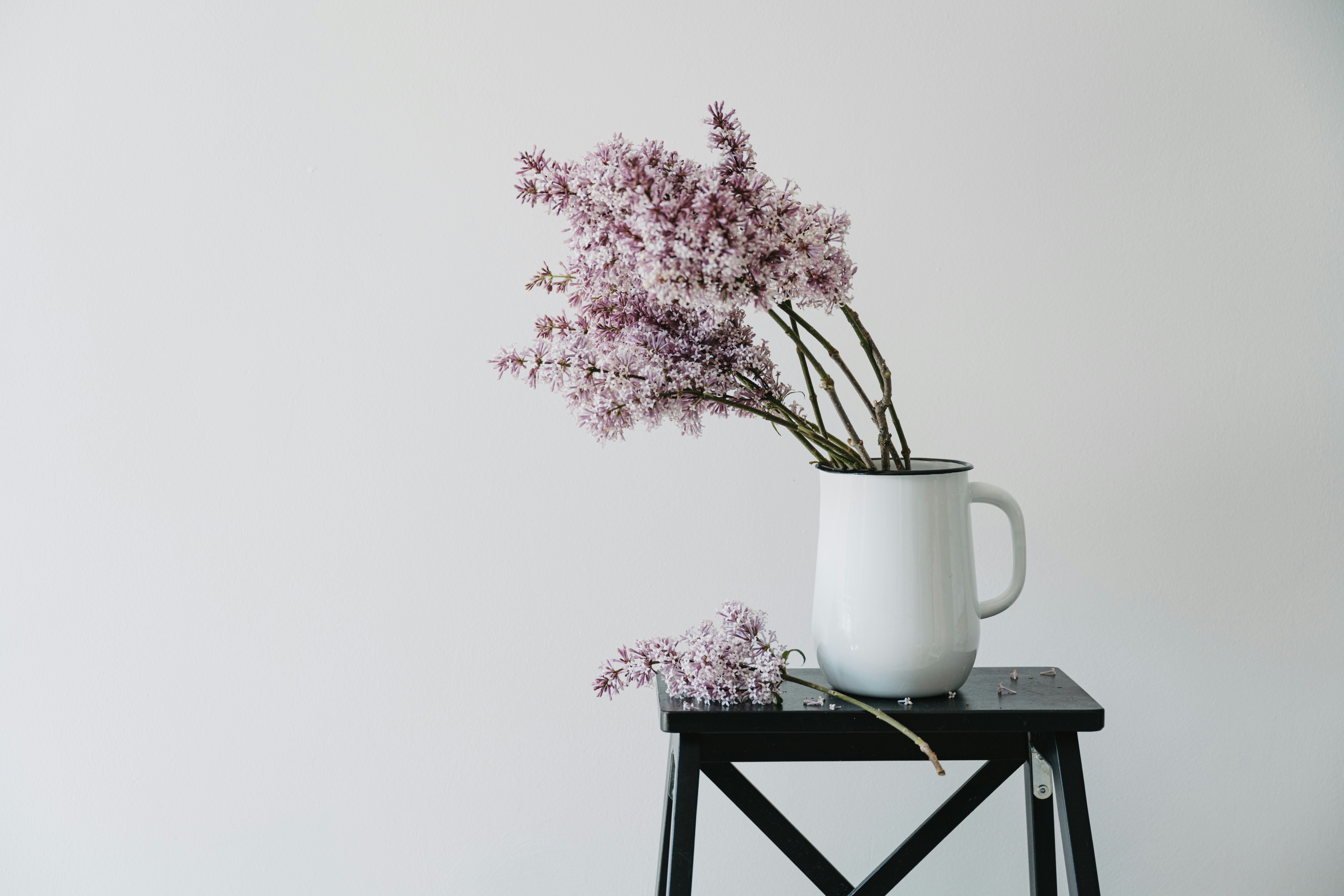 Foto Un jarrón con algunas flores sobre una mesa – Imagen Ramas lilas ...