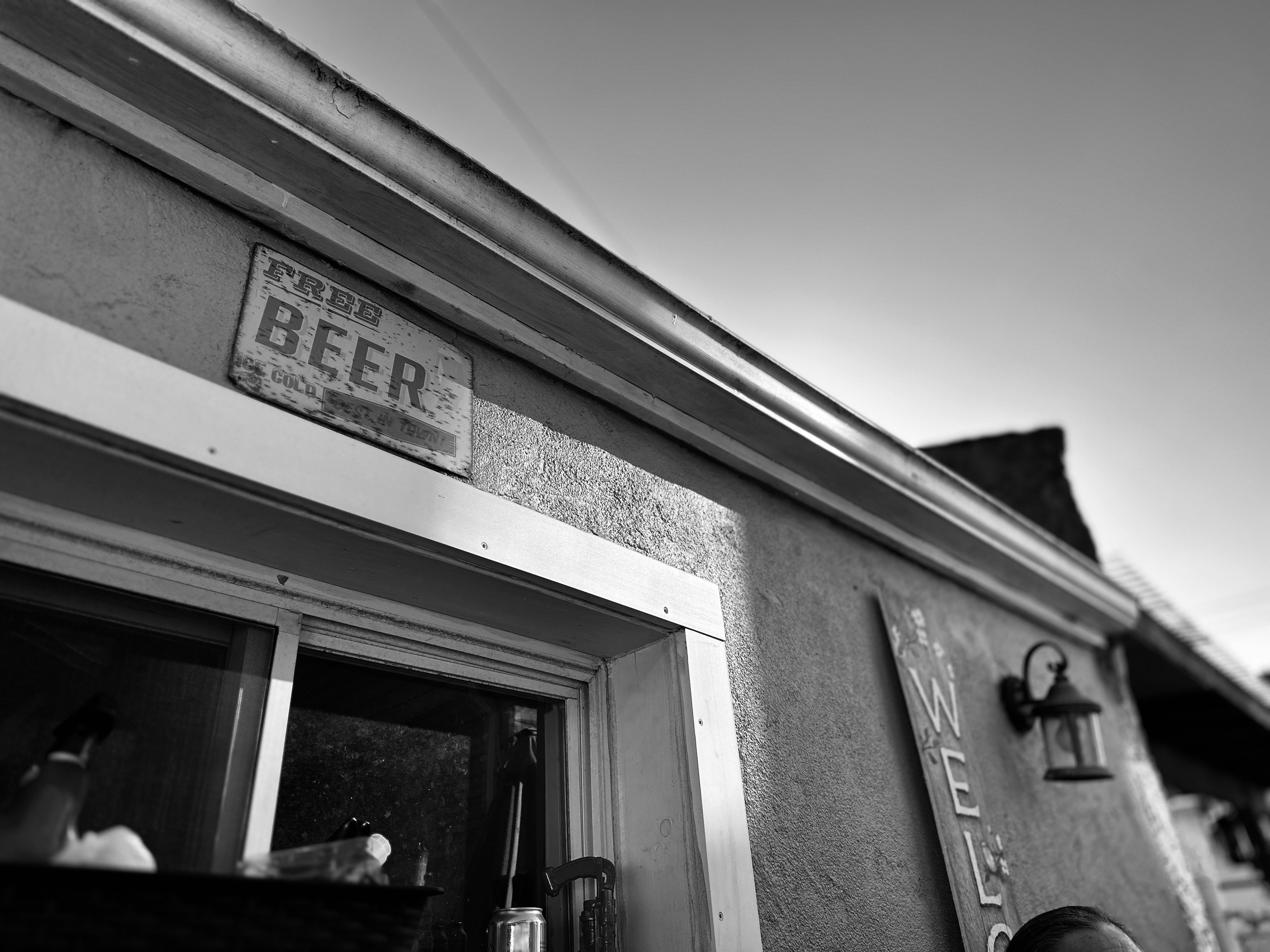 Monochrome Beacon: The Beer Sign Above a Weathered Storefront