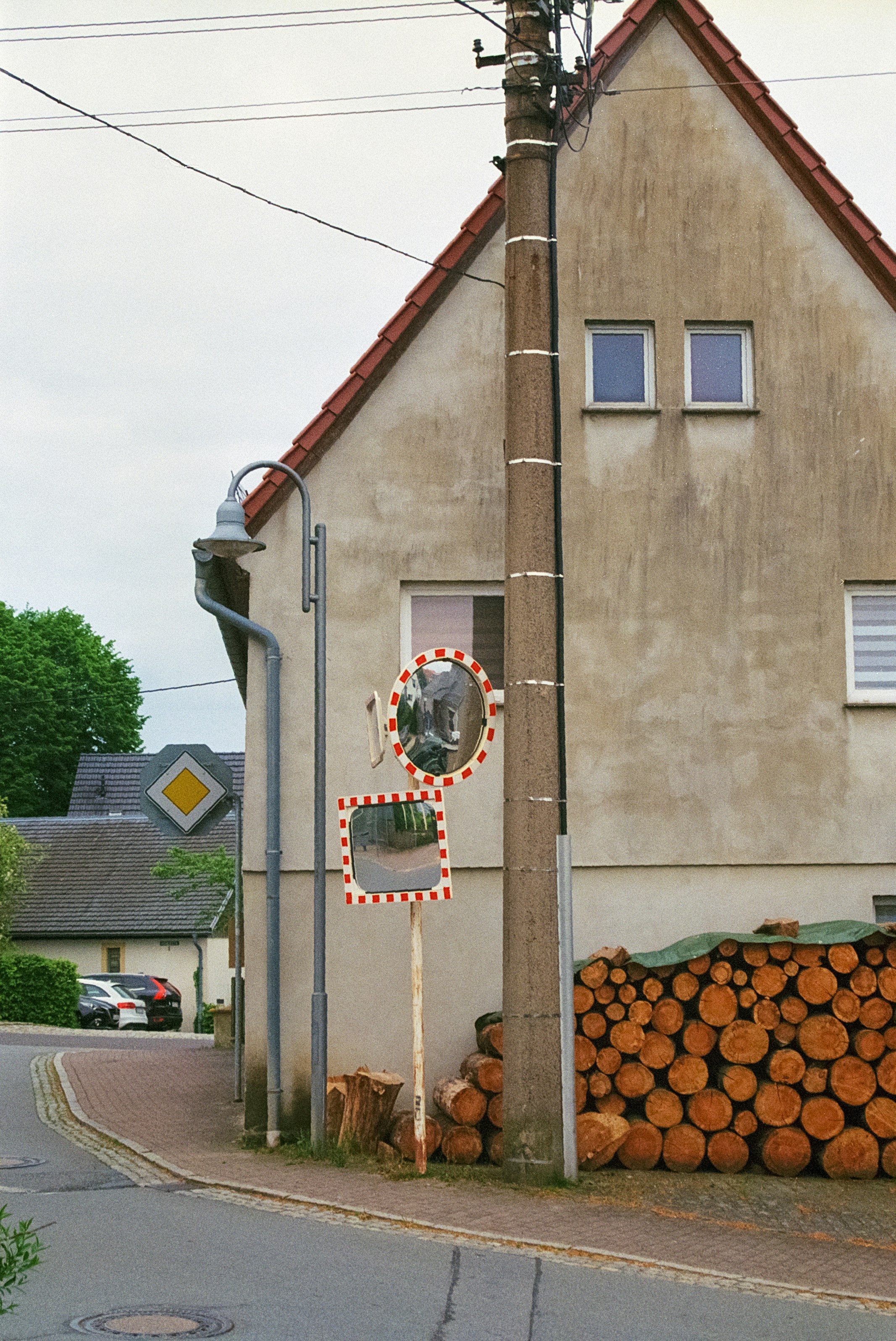 Red-Rimmed Signposts Framing a Quiet Street by a Pile of Logs