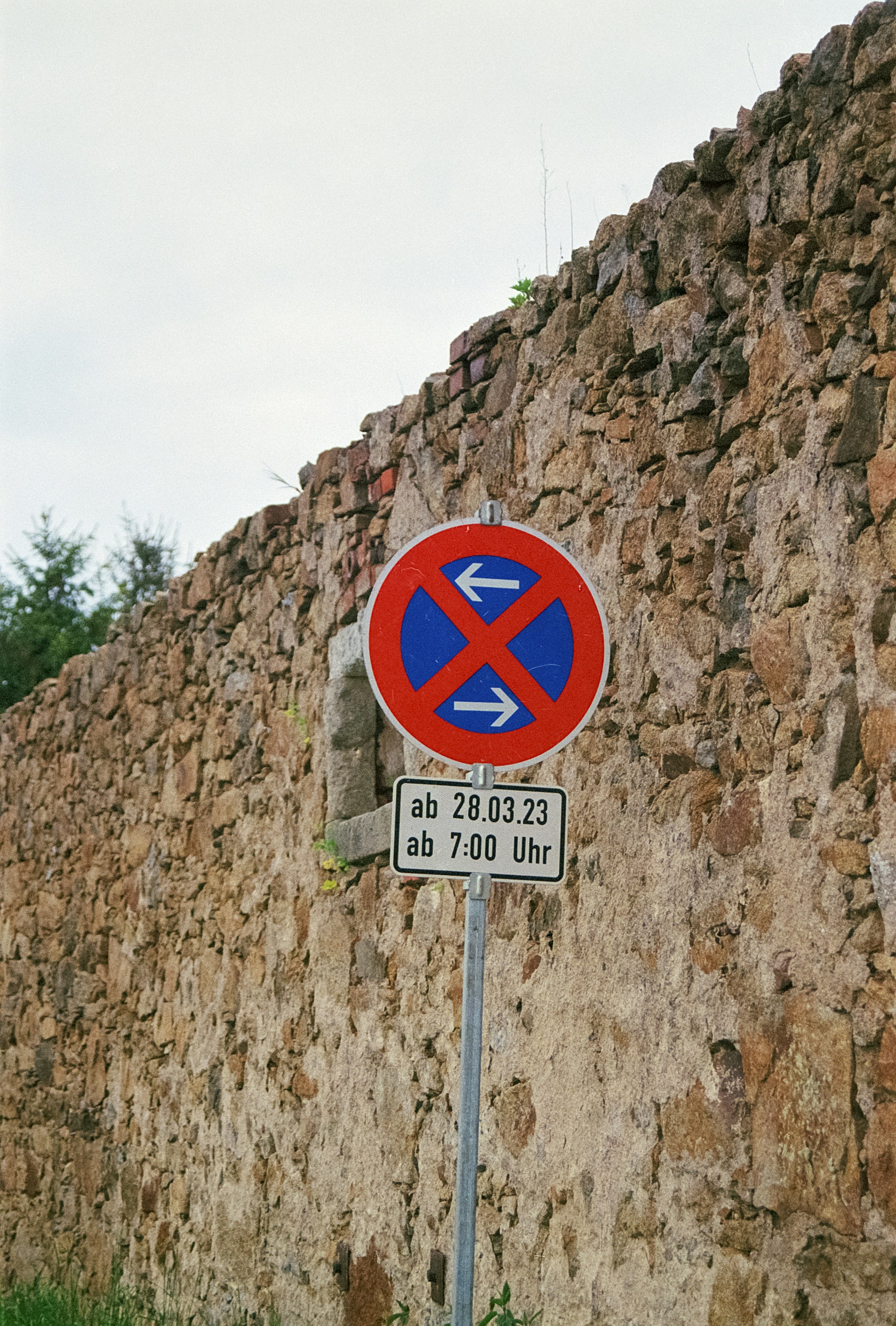 A red and blue street sign next to a stone wall photo – Free City Image ...