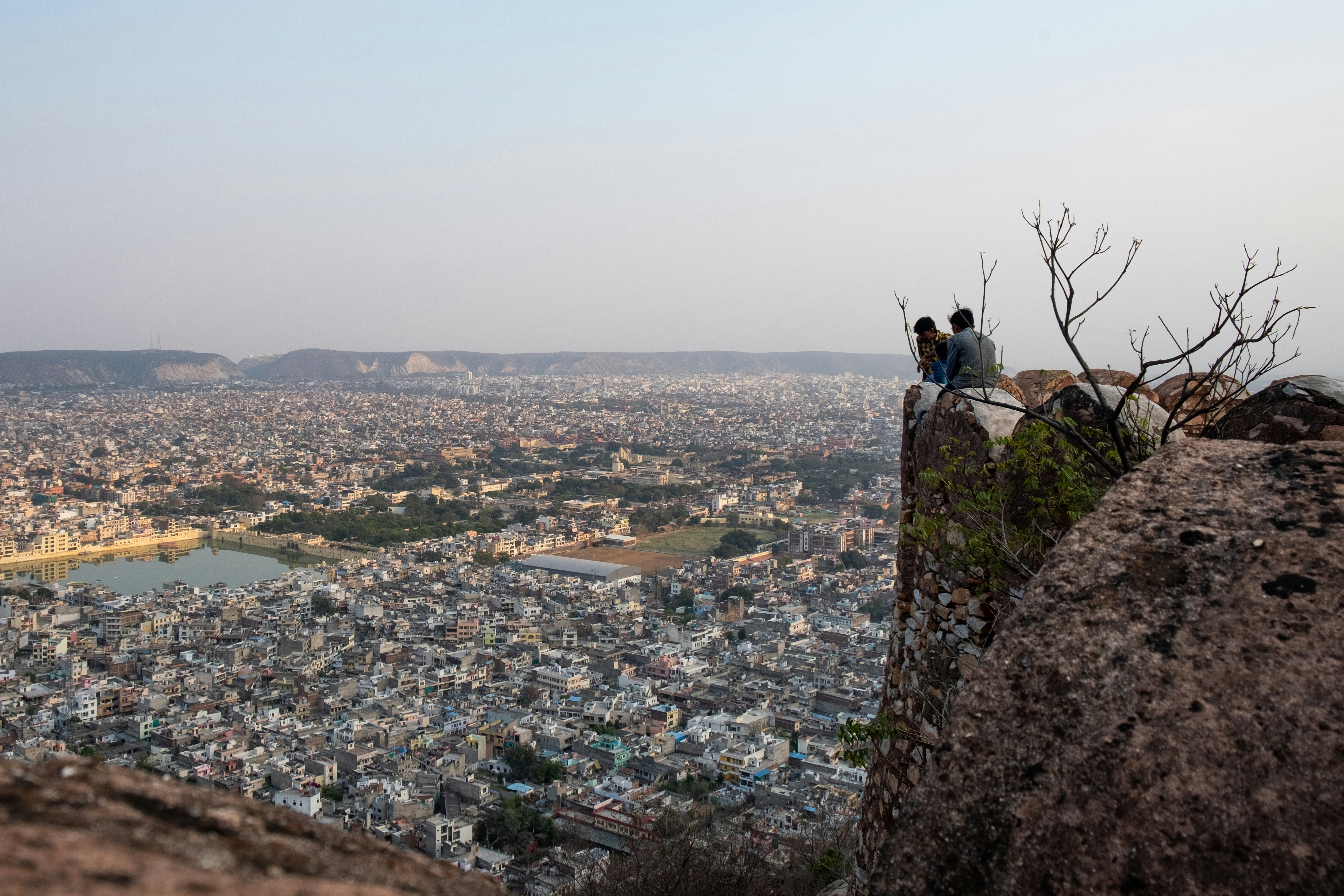 On the Edge: Two Travelers Stand Above a Sea of Rooftops
