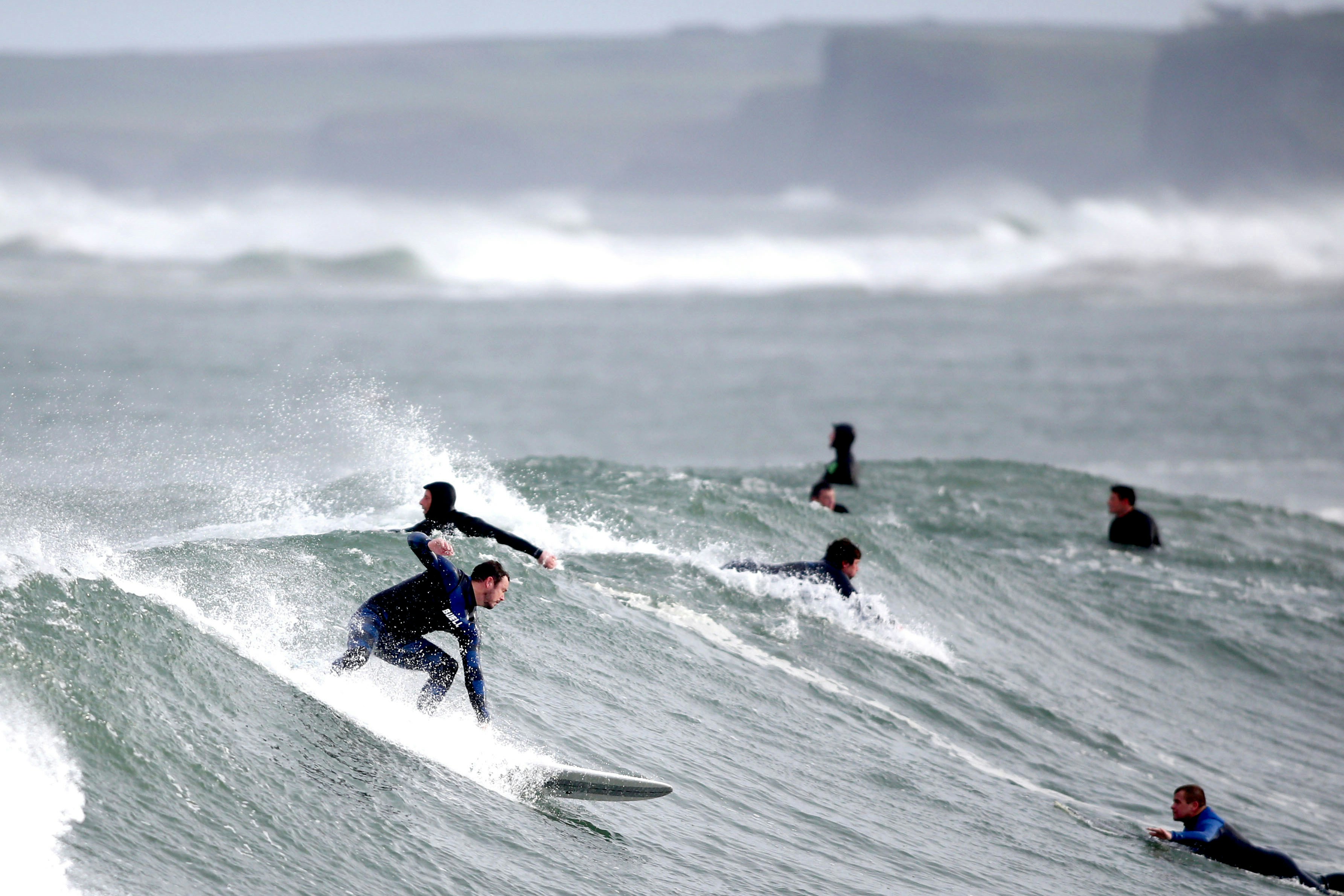 A group of people riding surfboards on top of a wave photo – Free Sea ...