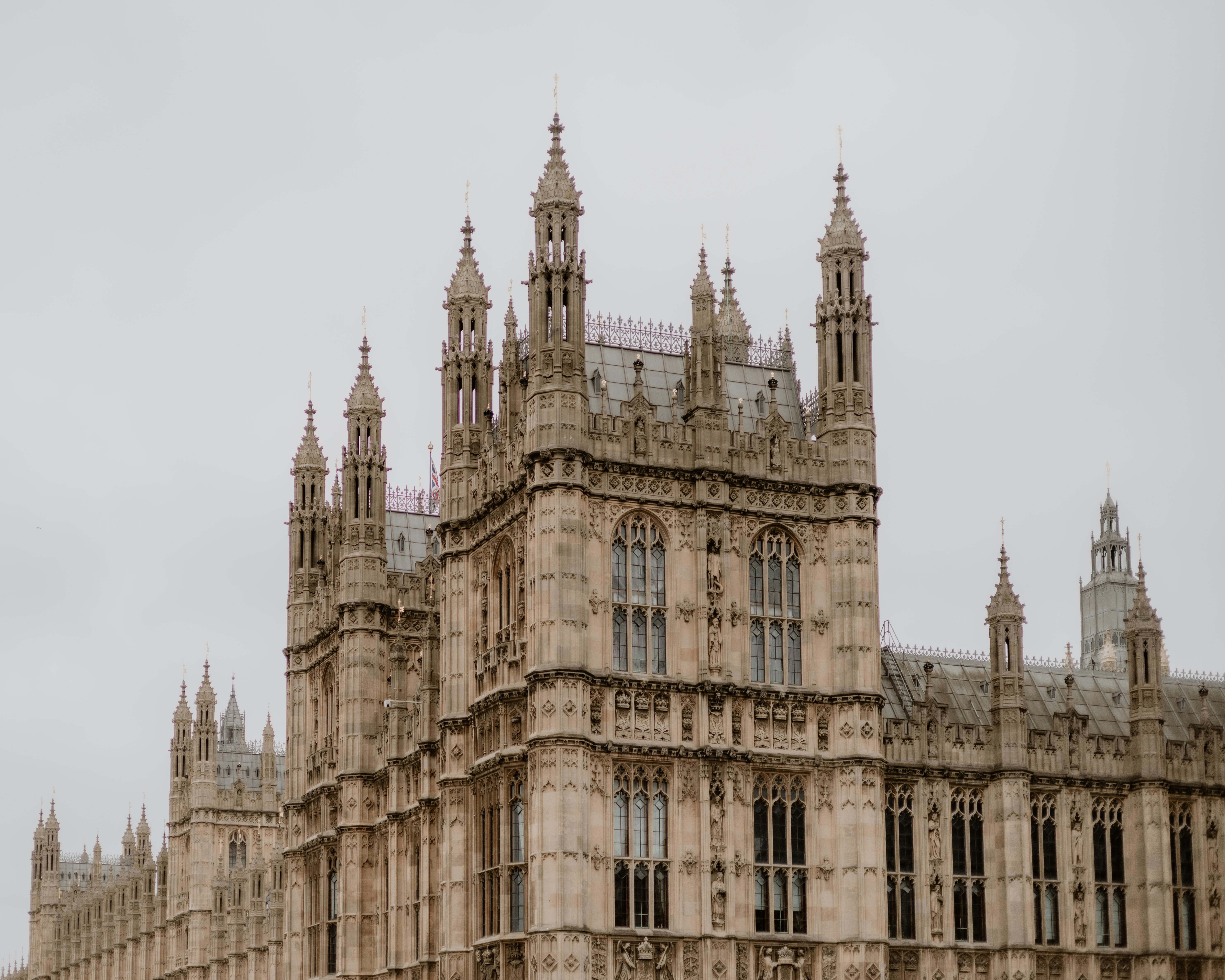 Intricate Gothic architecture of the Palace of Westminster, showcasing its towering spires and detailed stonework under a cloudy sky.