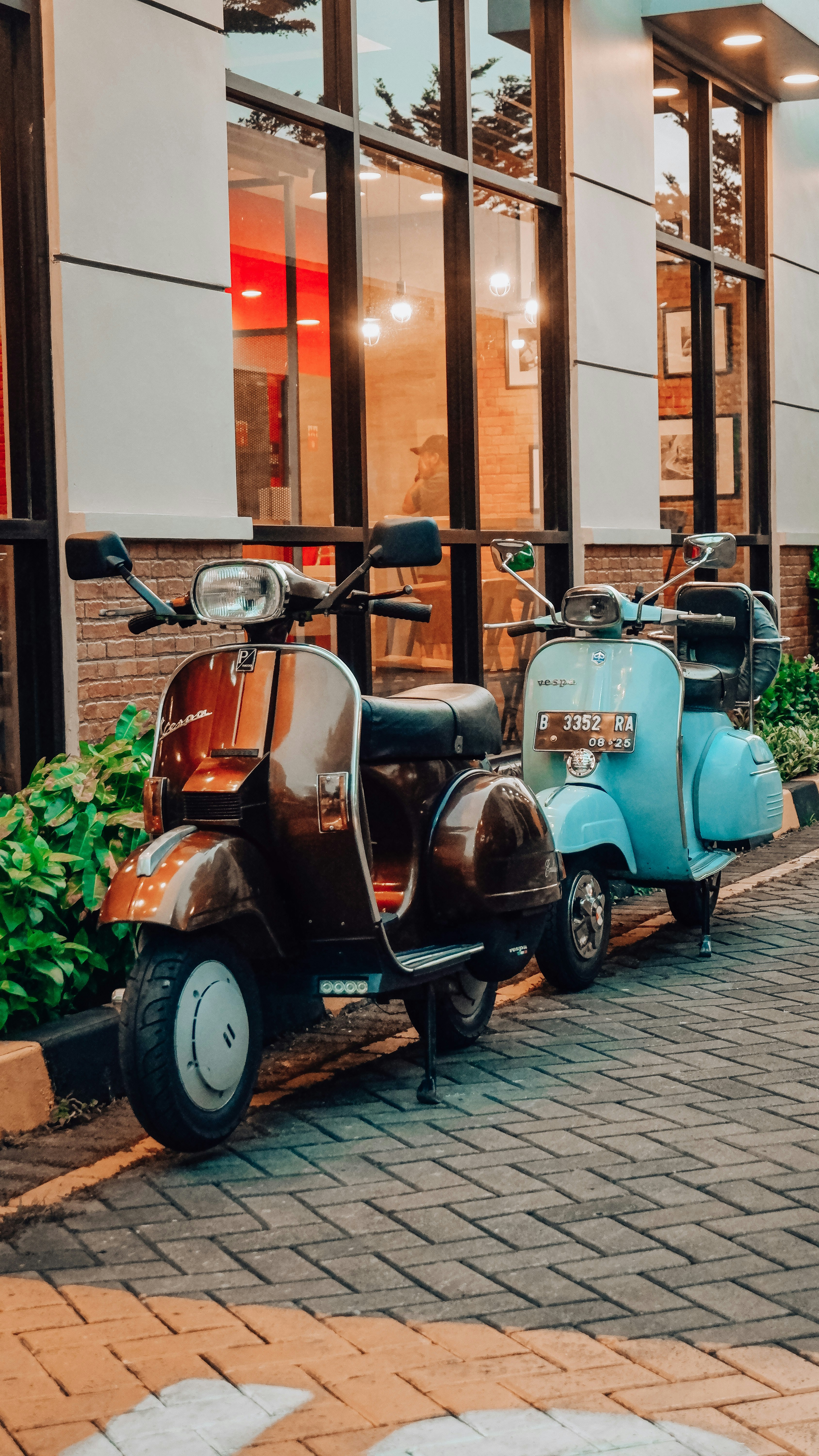 Amber Vespas by a Glass-Front Café at Dusk