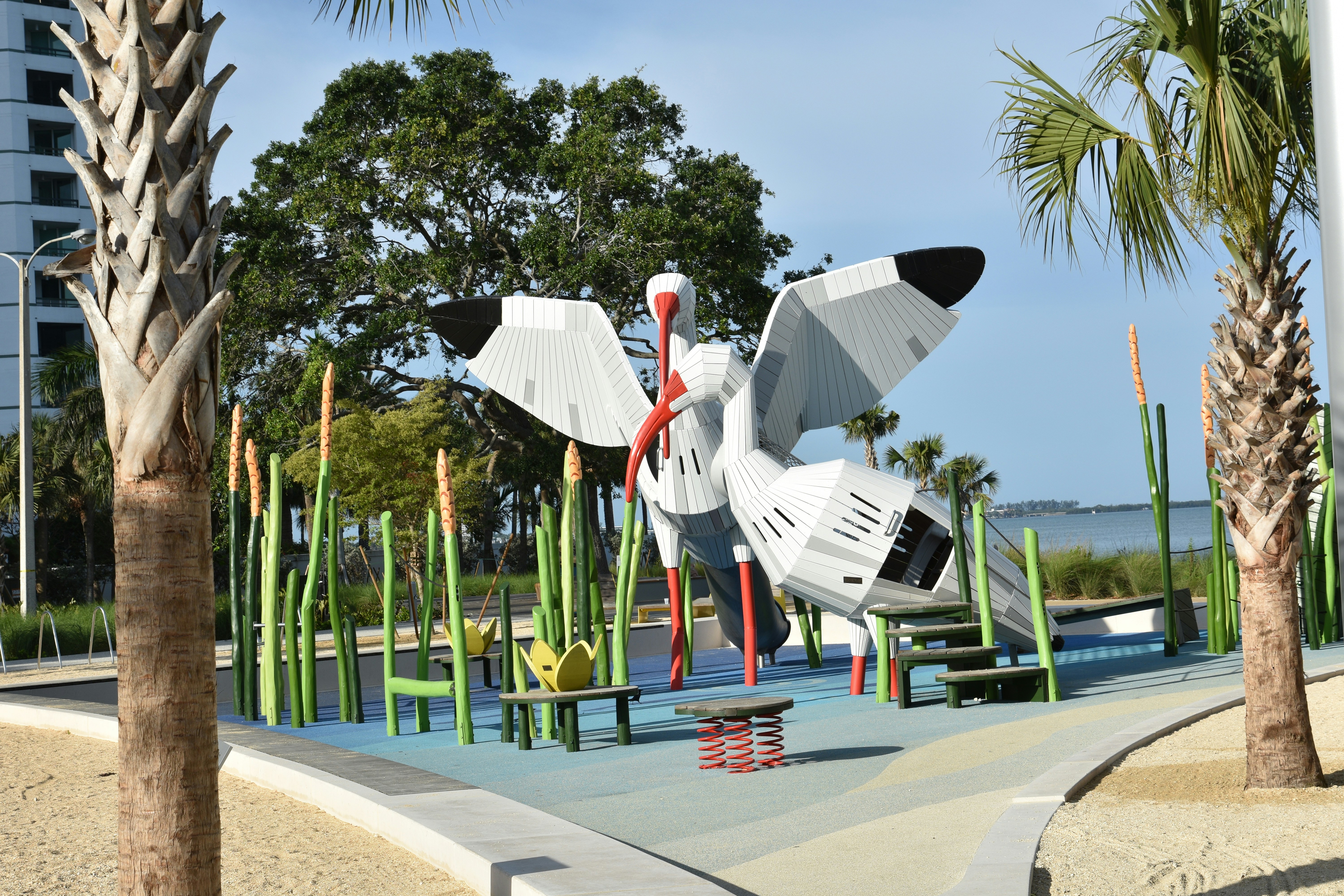 Winged Crane Over a Sunlit Palm Plaza