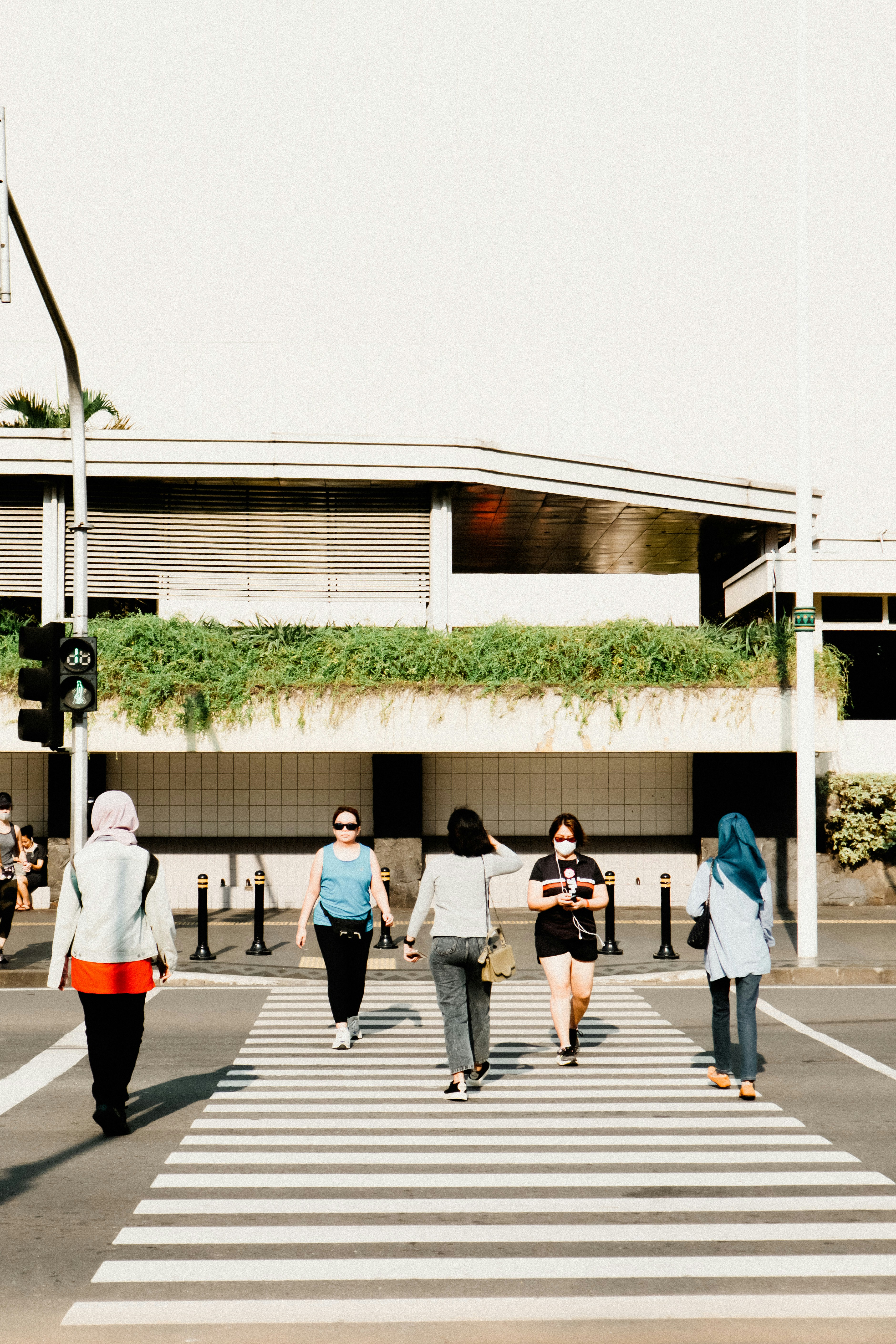 Crosswalk Confluence: Pedestrians Pace Under a Sleek Urban Overhang