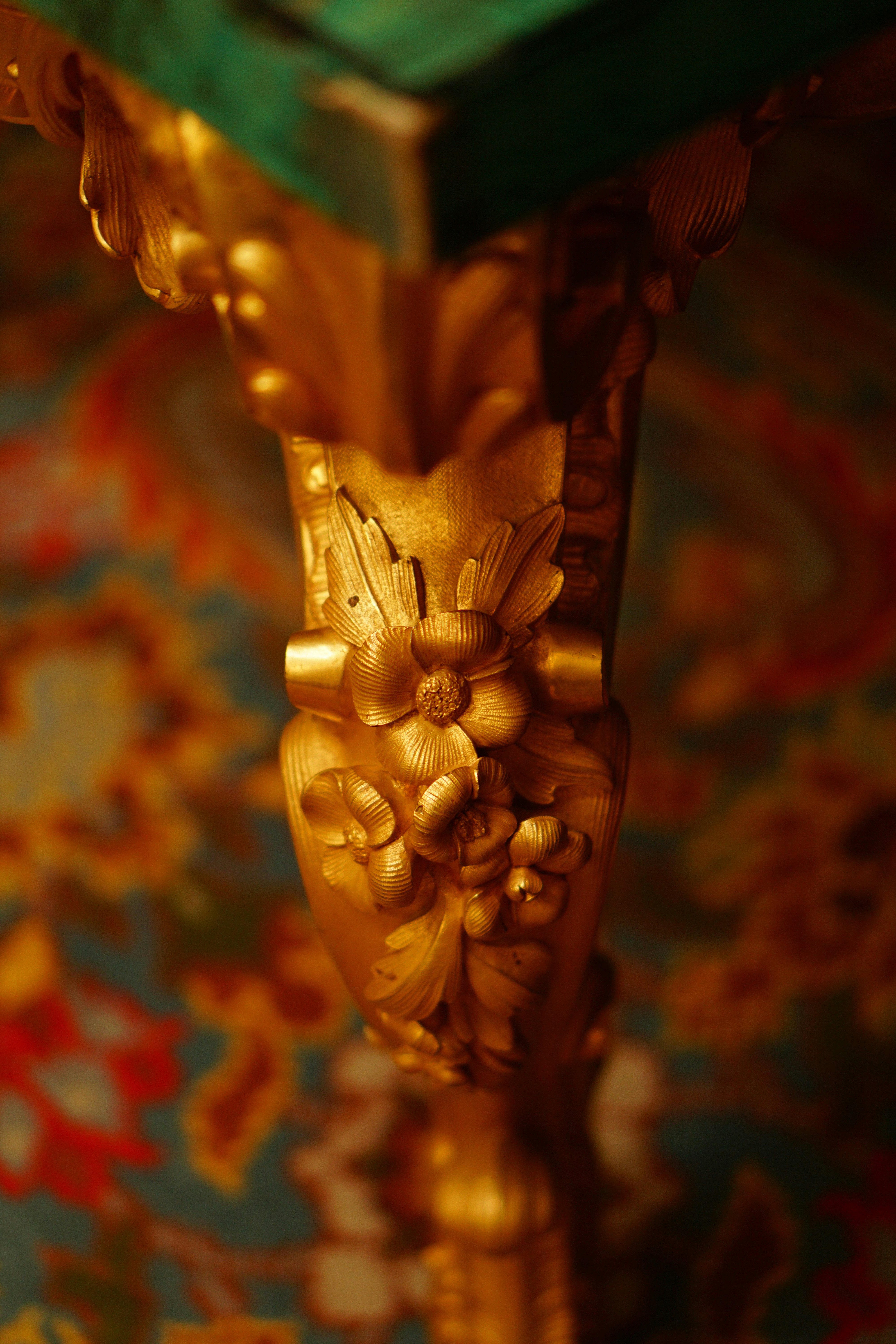 Gilded Bloom: Close-Up of Floral Carving on a Table Leg Bathed in Amber Light