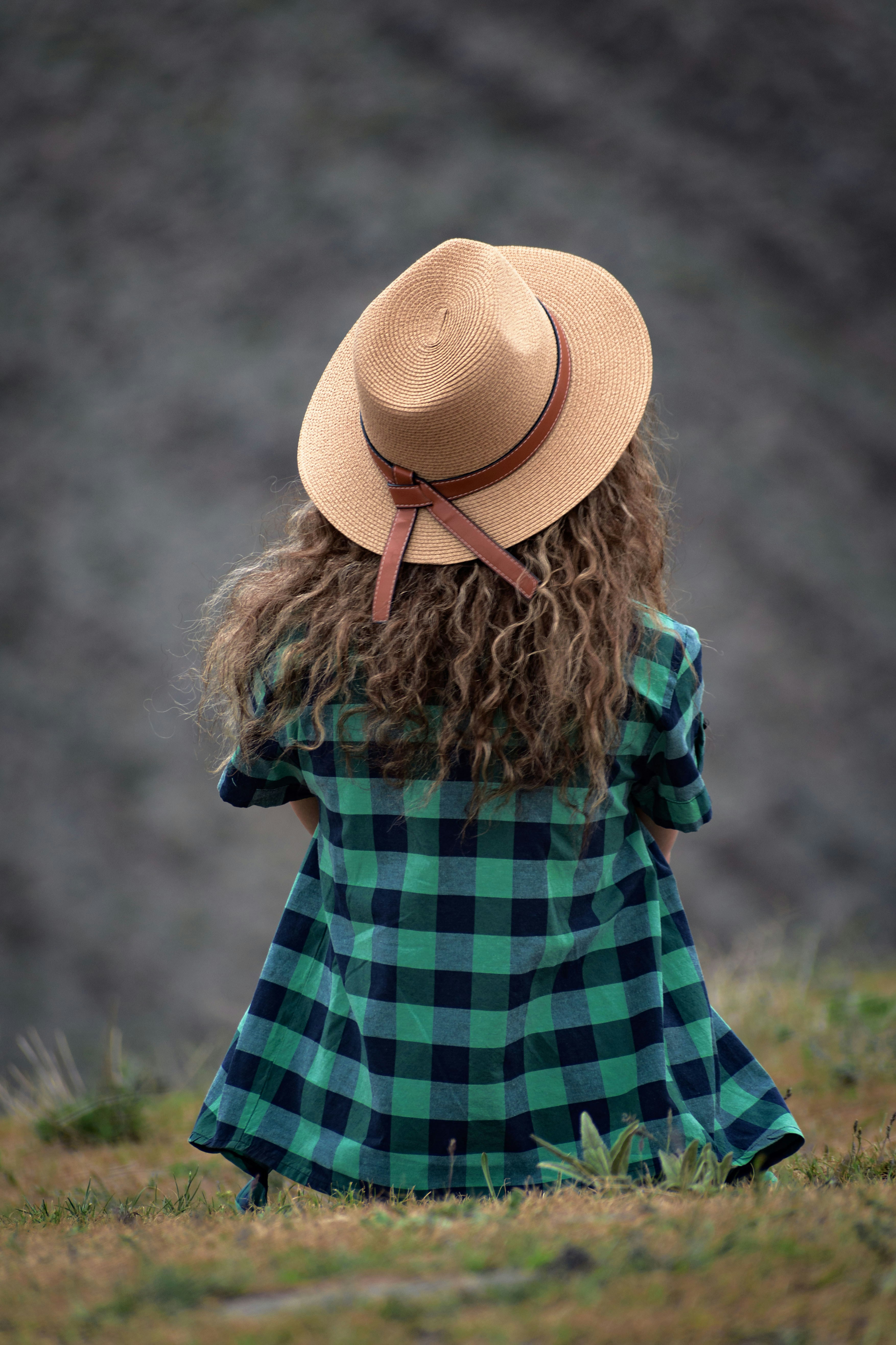 Facing Away in Plaid: A Quiet Moment Under a Straw Hat