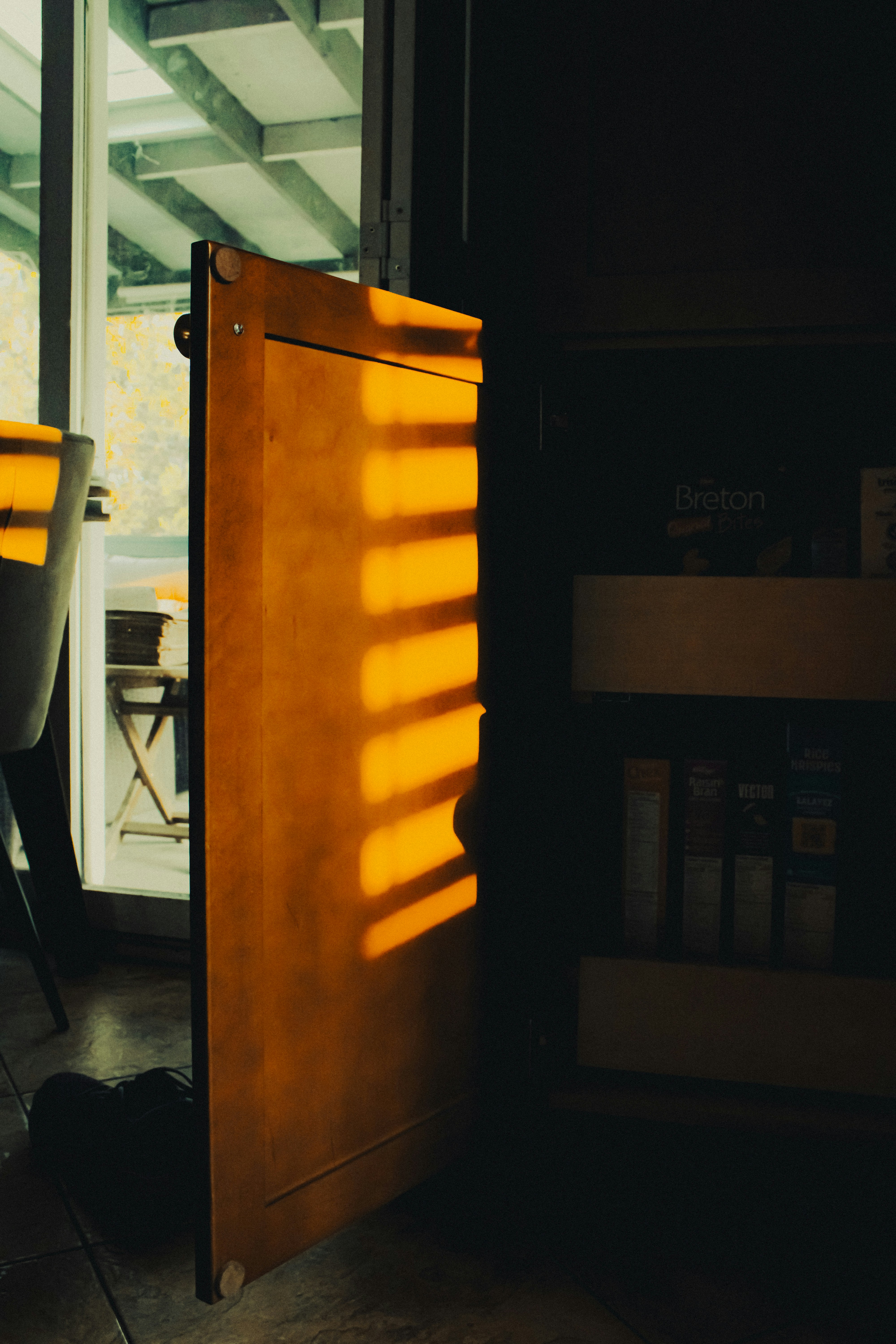 Sunlit orange door slab casting elongated stripes into a dim interior