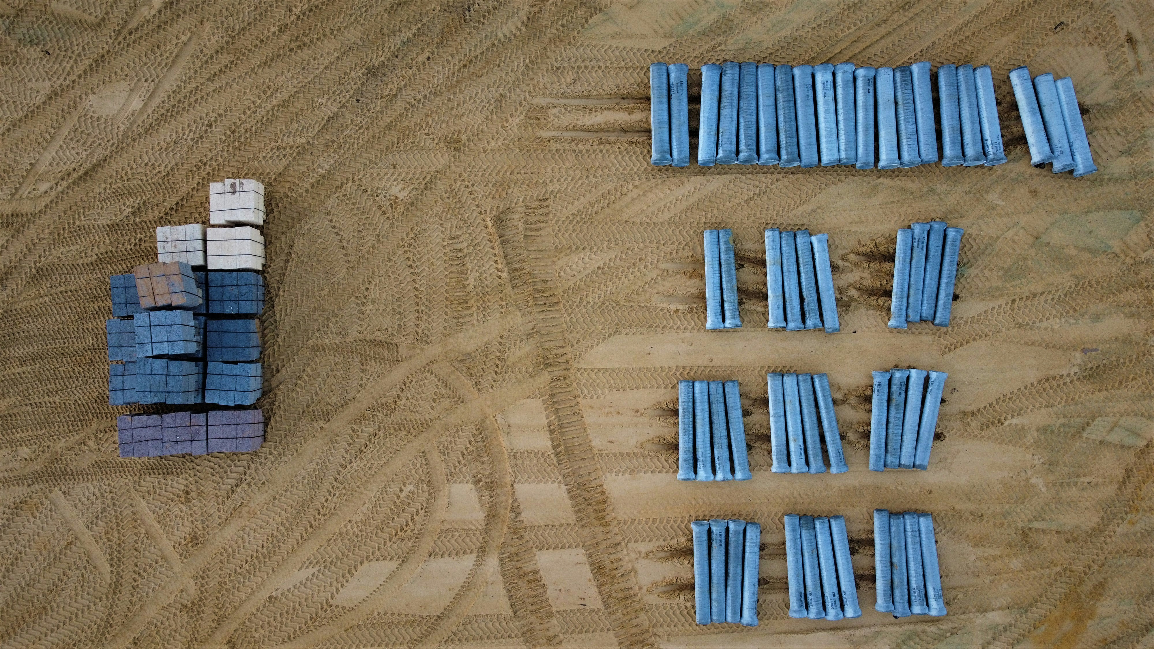 Blue Timber Blocks Align: Aerial View of Separated Stacks on Sand Surface