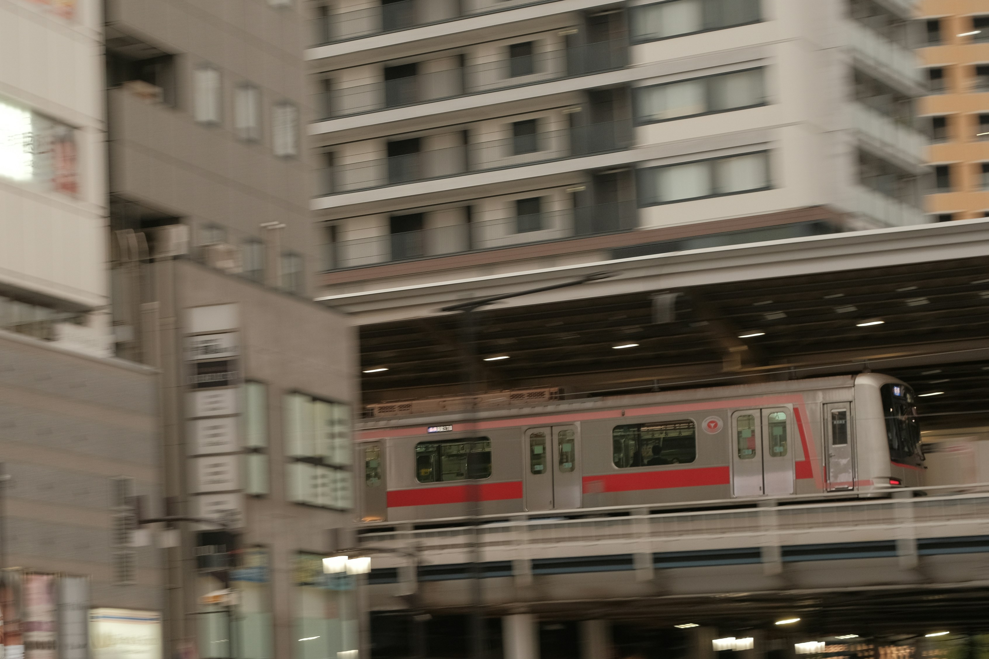 A sleek train glides past modern urban architecture, showcasing the dynamic interplay of transportation and city life.