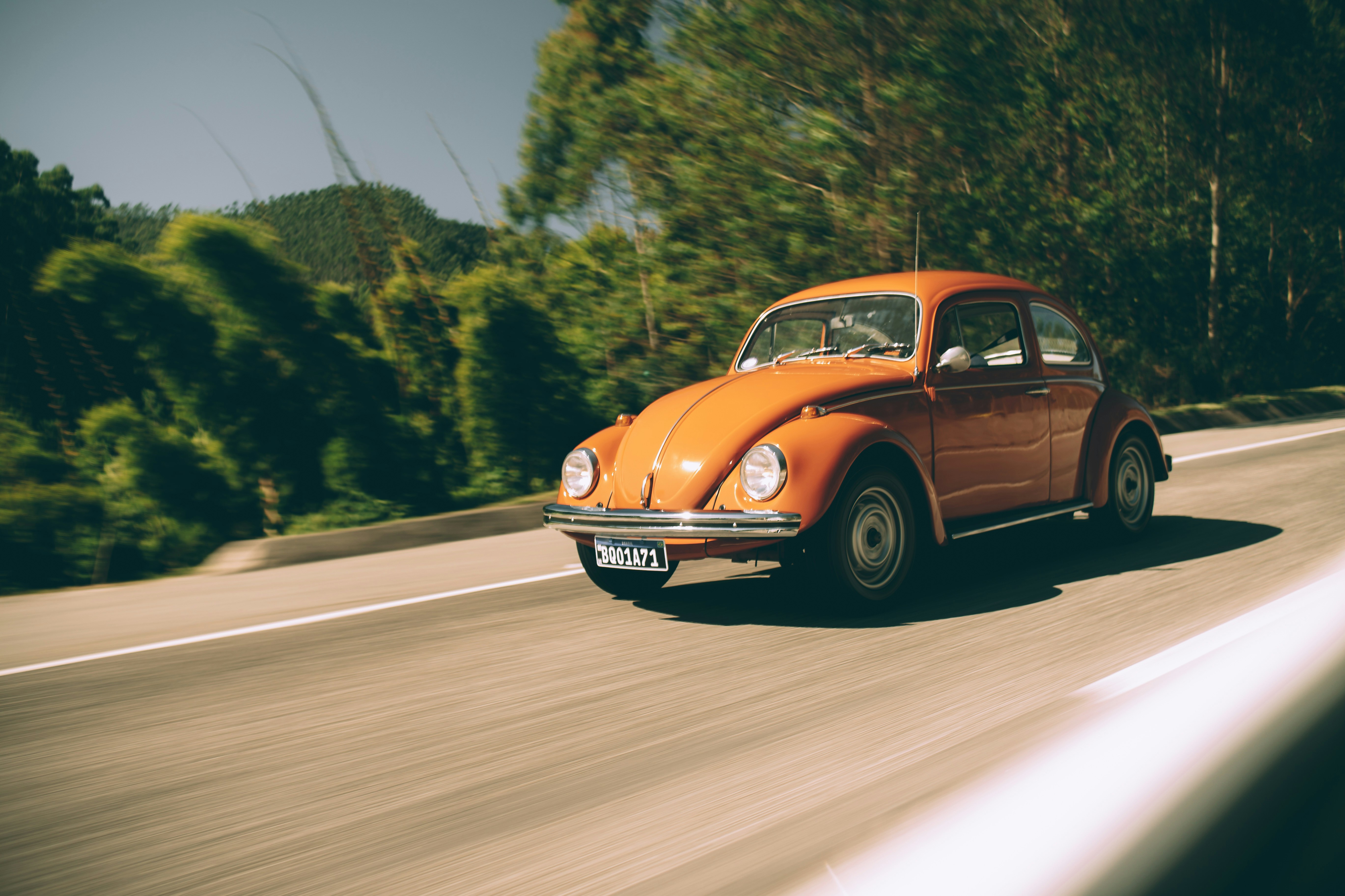 Velocity in Orange: A vintage Beetle surges along a sunlit highway