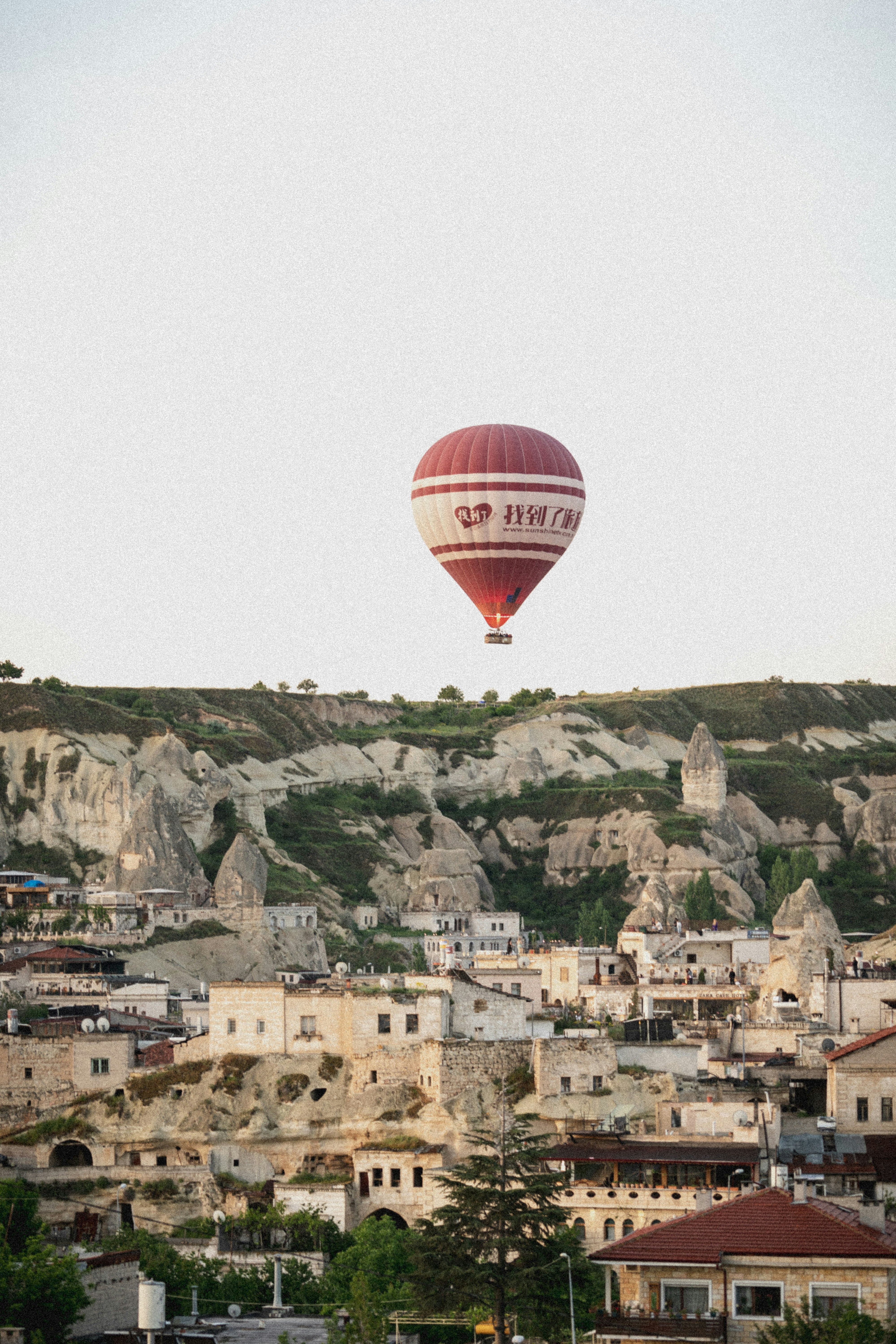 Balloon Drift Over Cliffside Village at Dawn