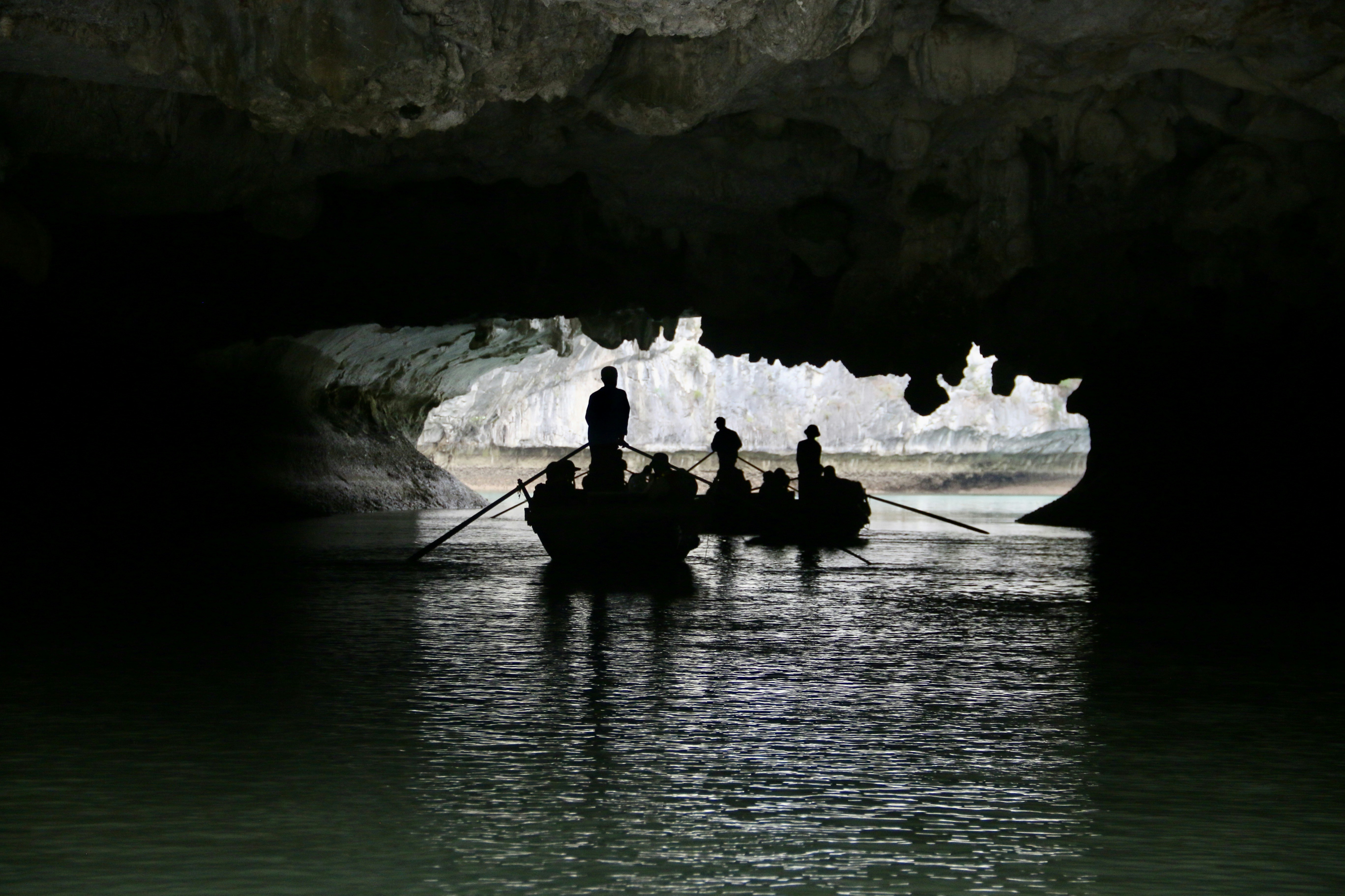 Rowing into Light: Silhouetted Explorers at a Cave's Portal