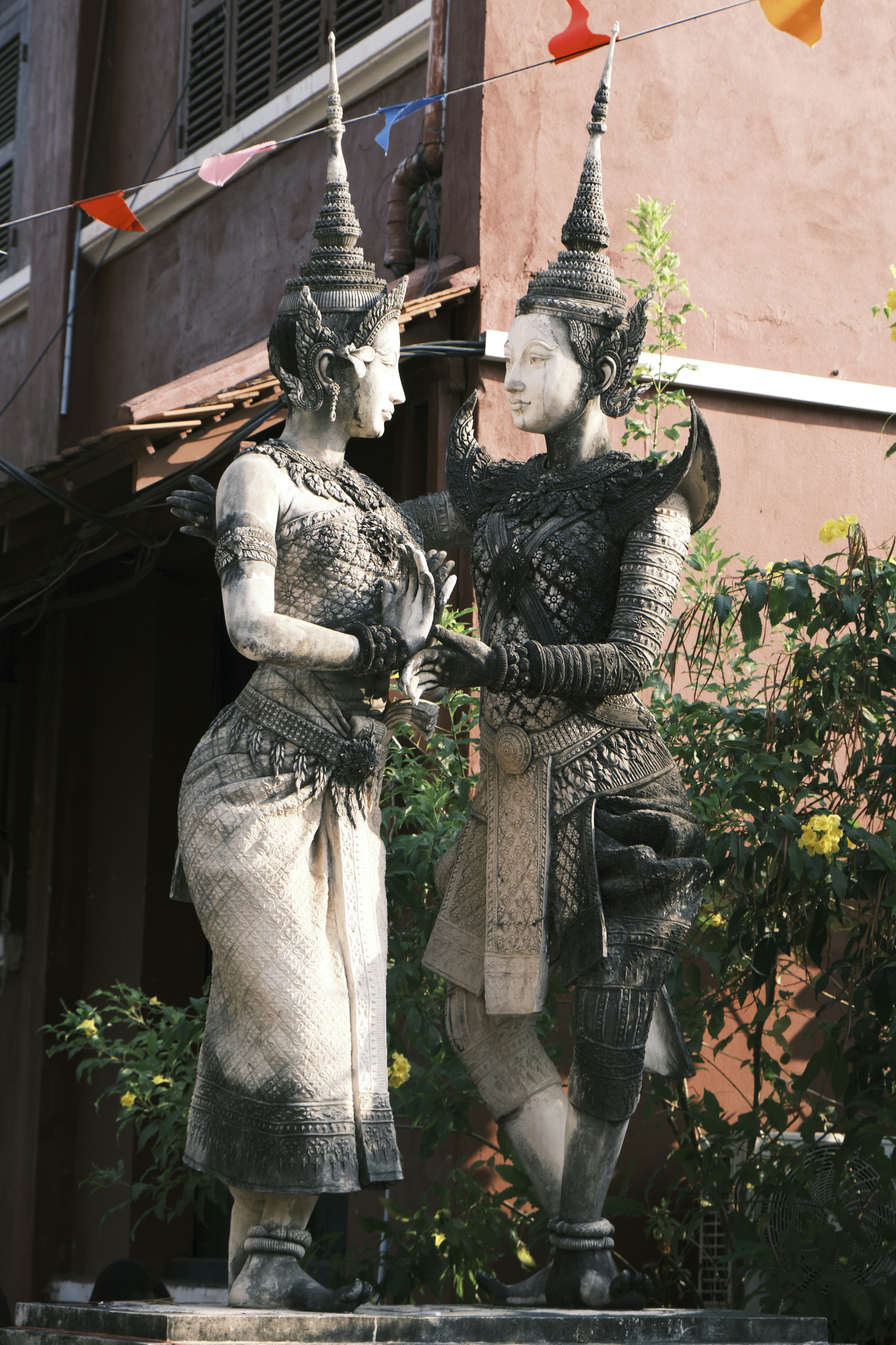 Whispered Exchange Between Twin Temple Dancers in a Sunlit Courtyard