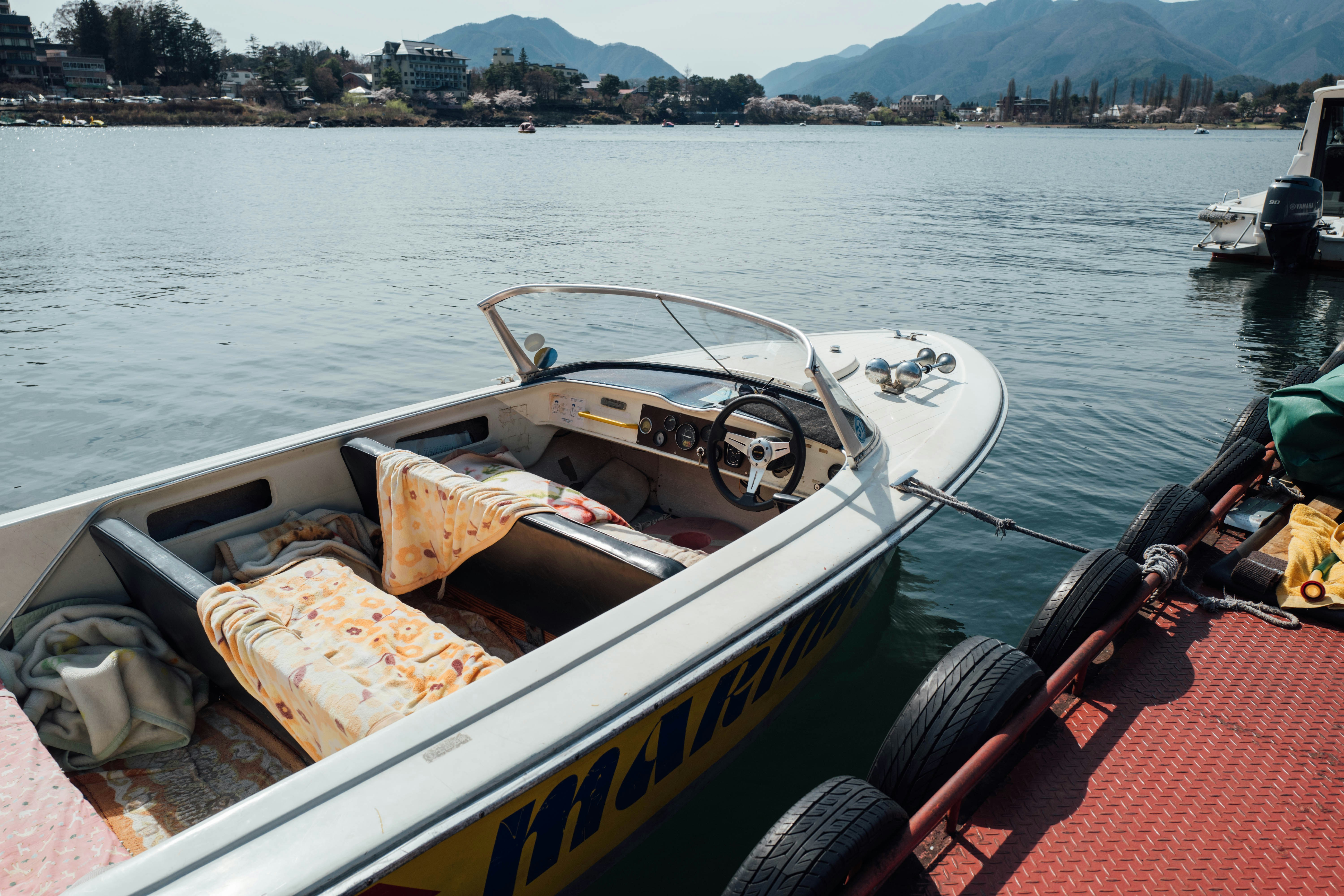 Small motorboat docked on a tranquil lake with misty mountains in the background.