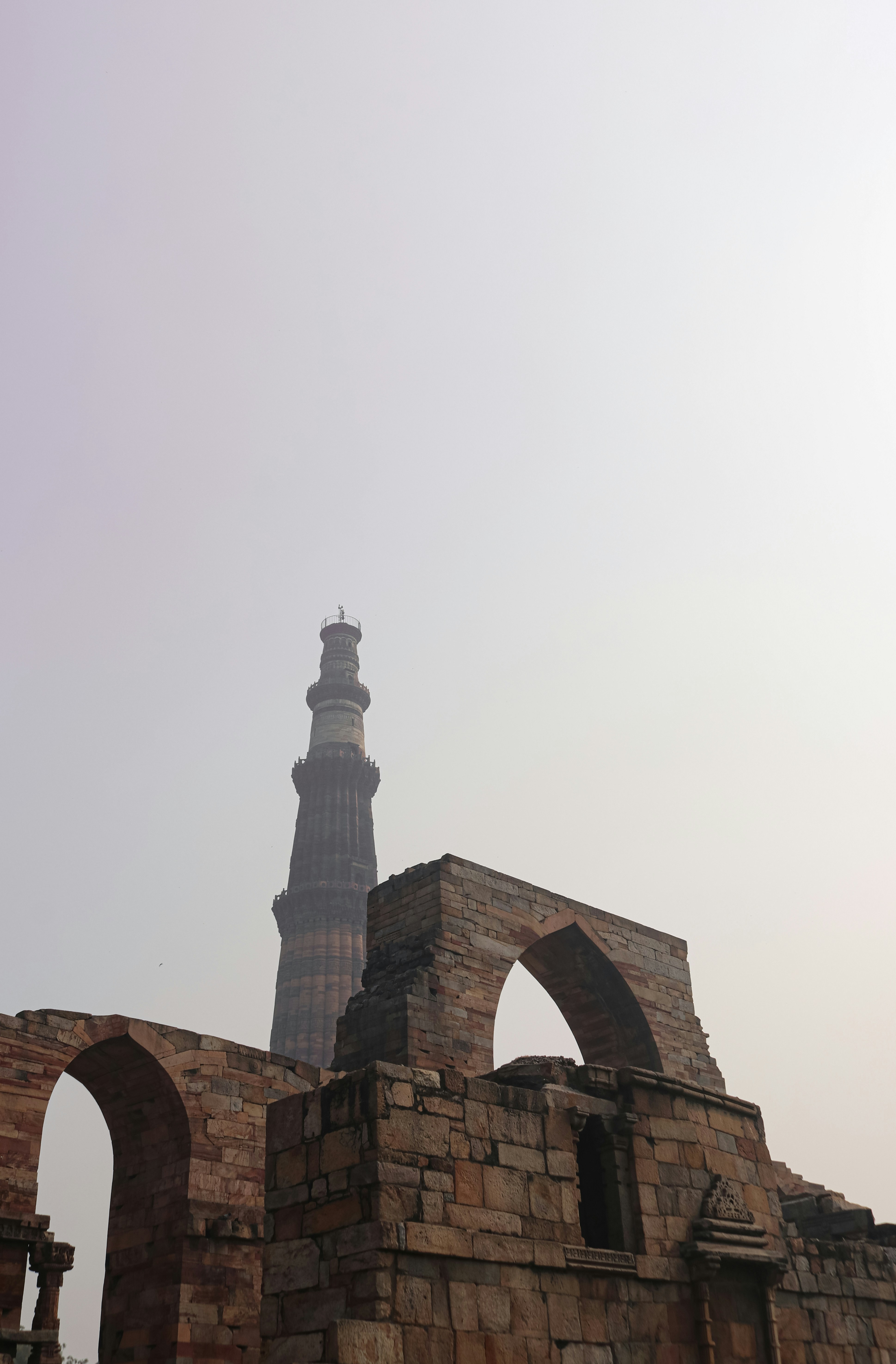Ruins and the Tongue of the Tower: A Weathered Archframe with a distant Minaret