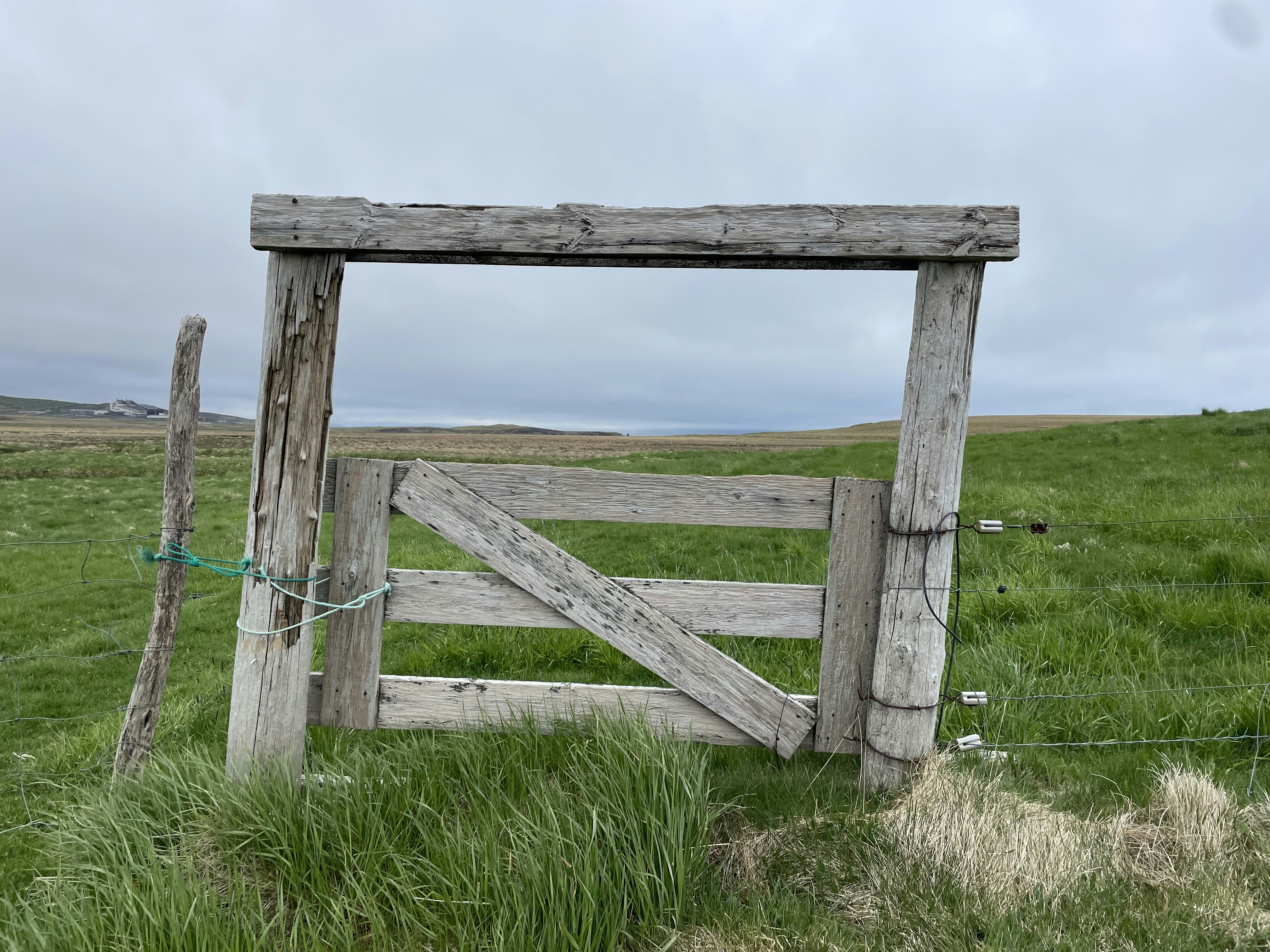 Weathered Gate Between Green Fields Under Wide Sky