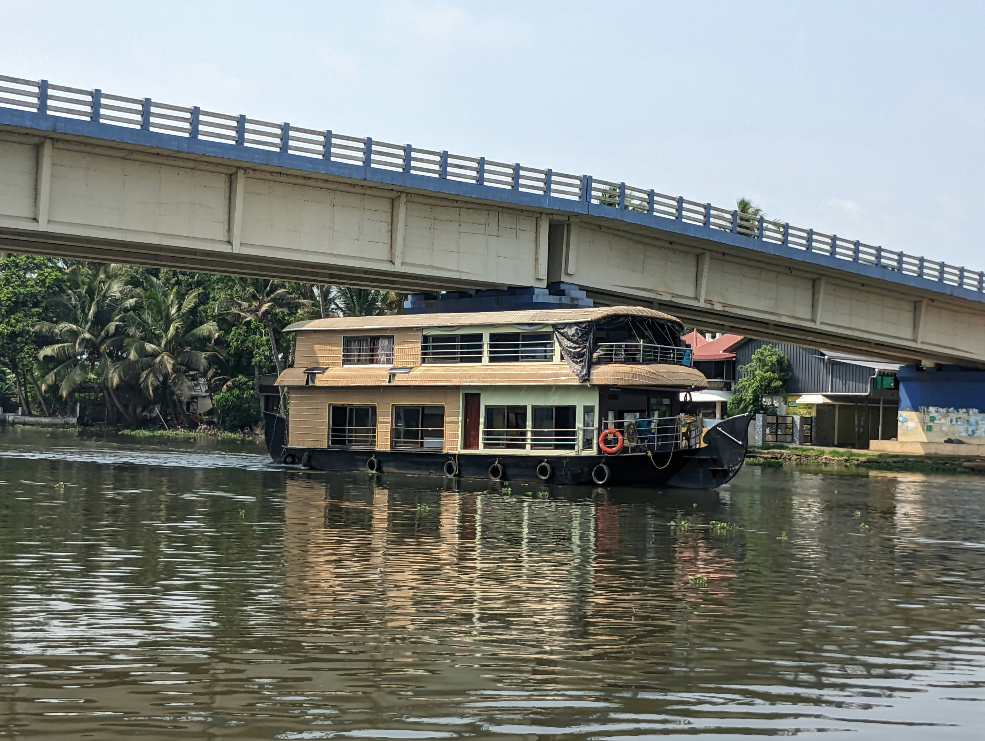 Ein Hausboot, das auf einem Fluss unter einer Brücke schwimmt Foto ...