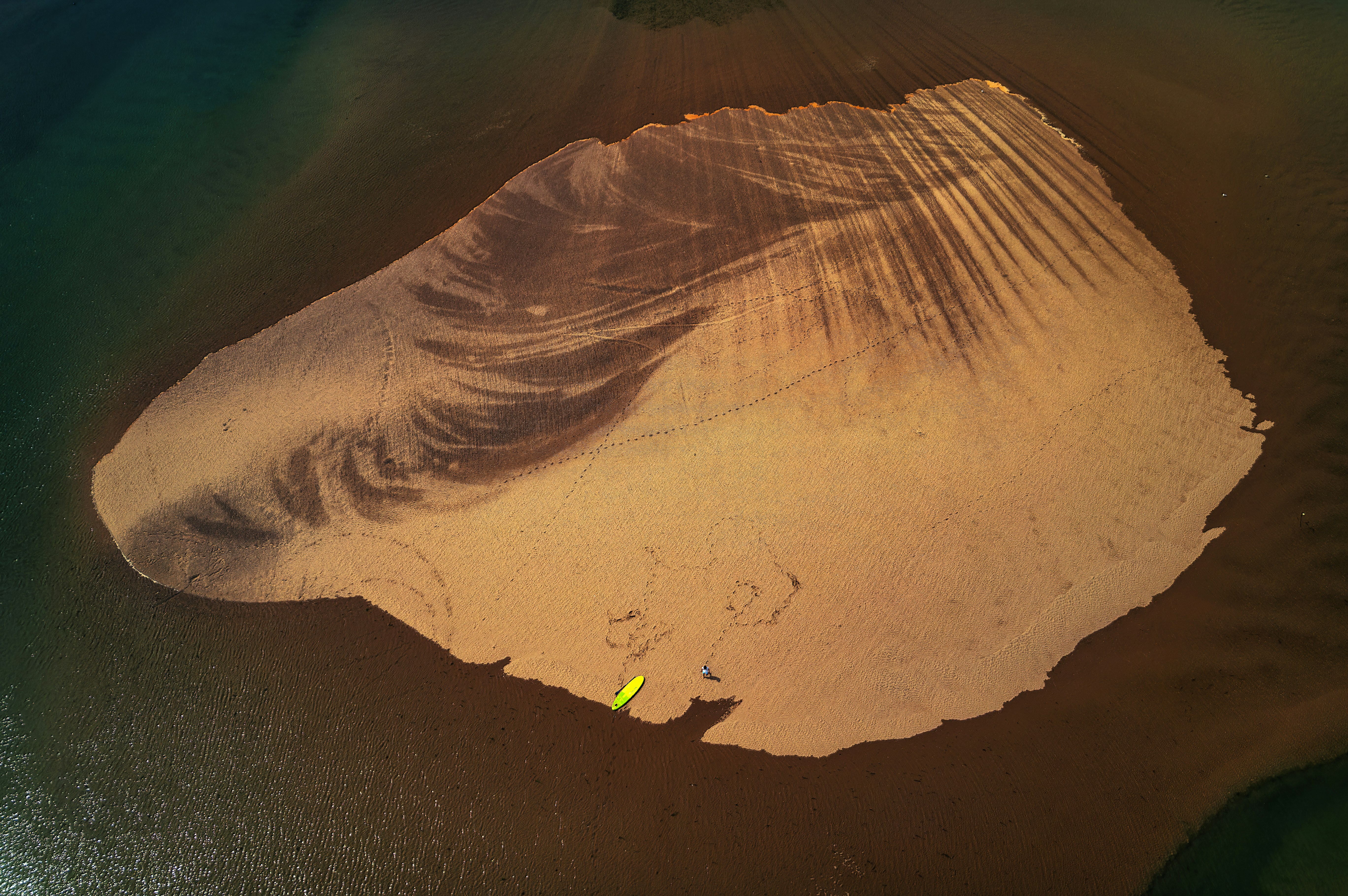 An aerial view of a sandy area with a yellow object in the middle of it ...