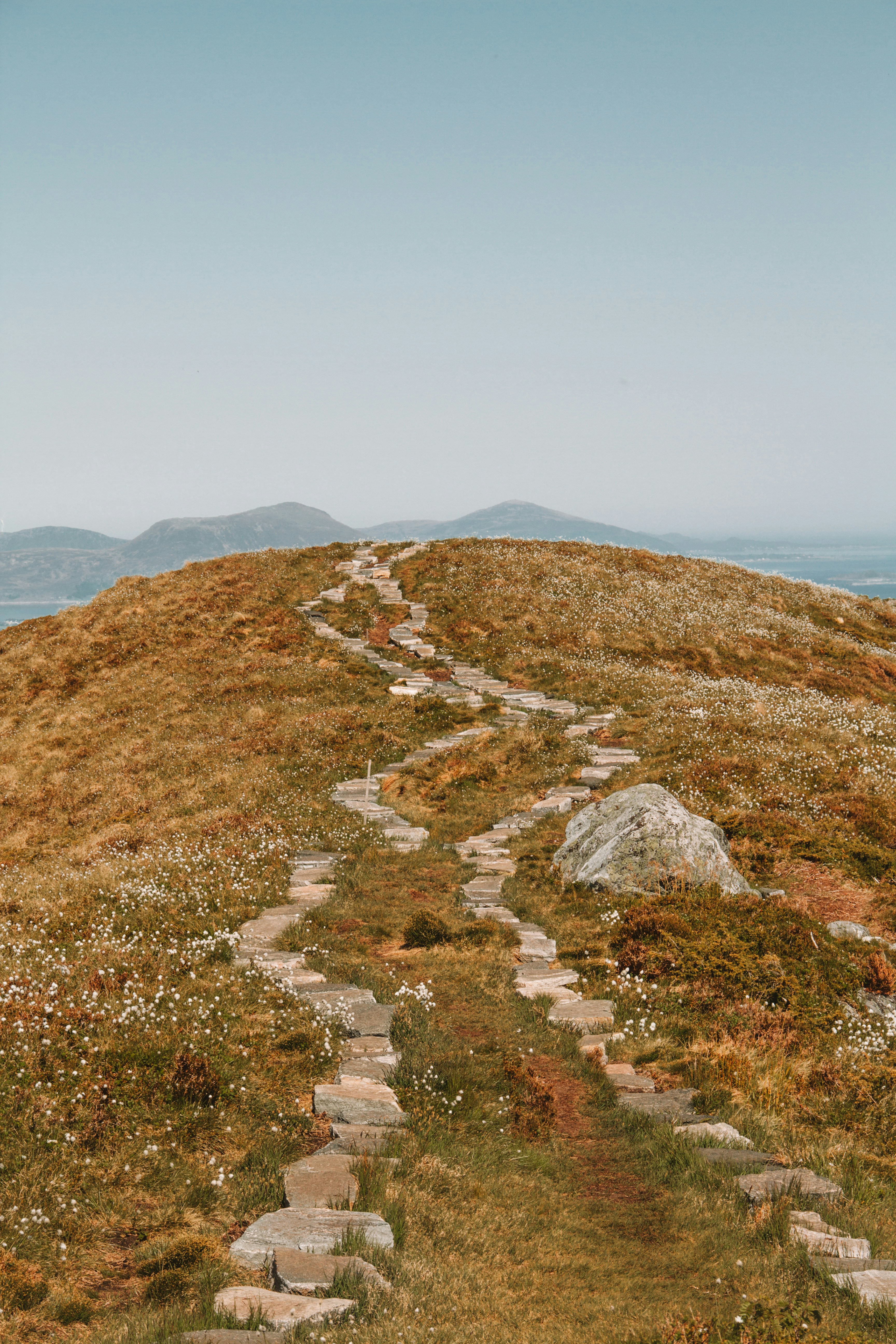 A path going up a hill with a view of the ocean in the distance photo ...
