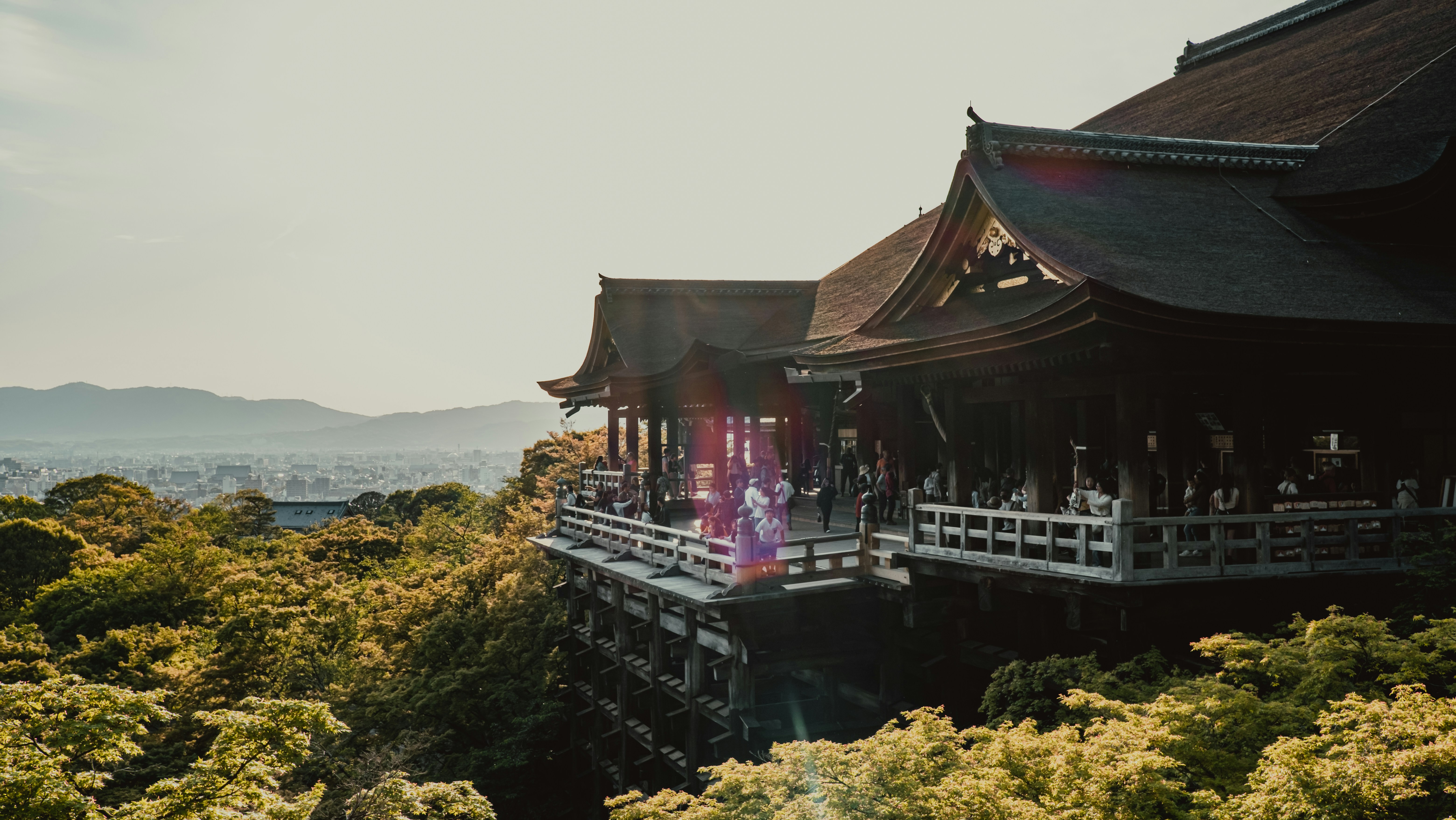 Historic Kiyomizu-dera temple perched on a lush hillside under a bright sky.