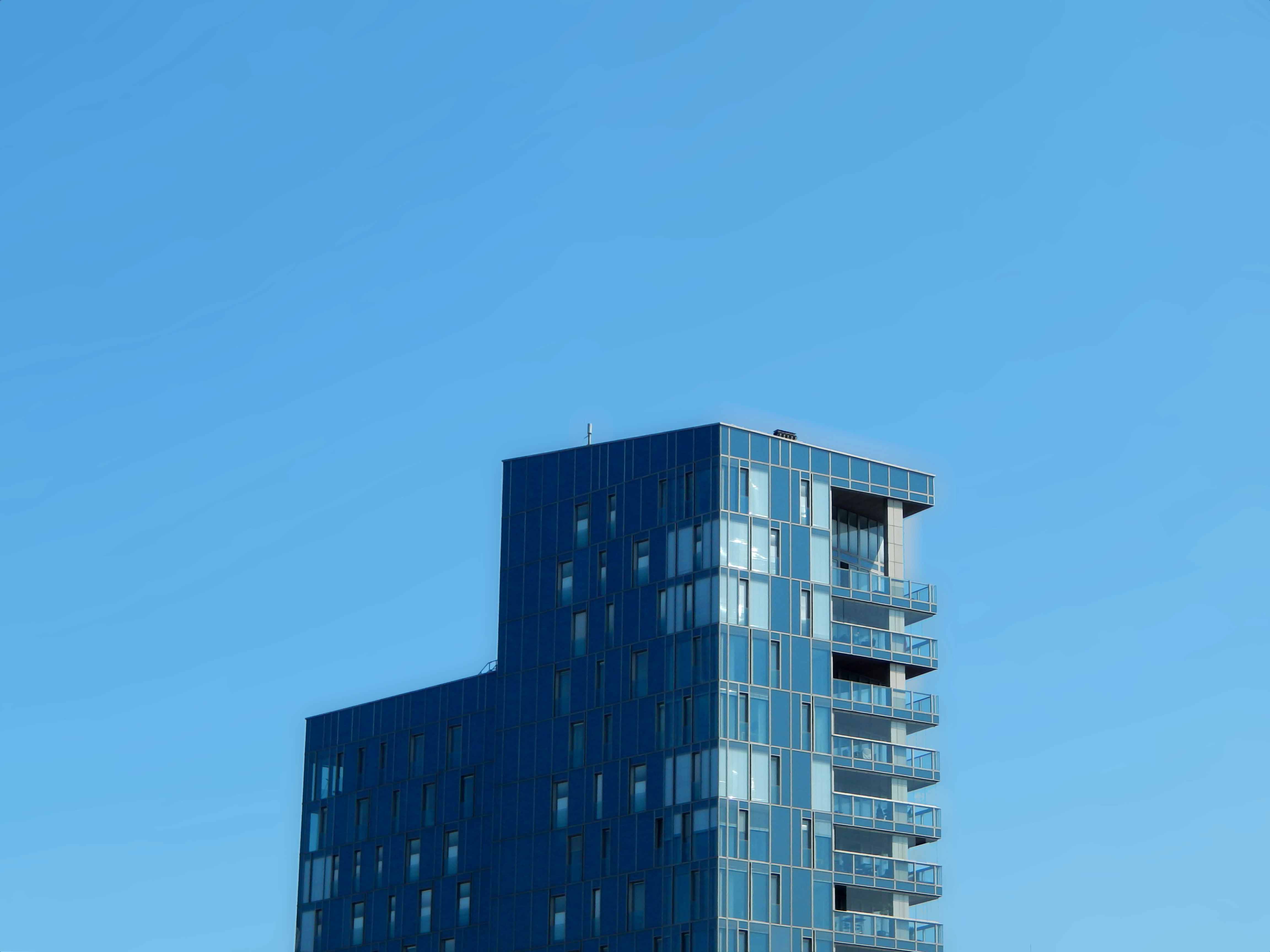 a top of the glass business building with the blue sky in the background