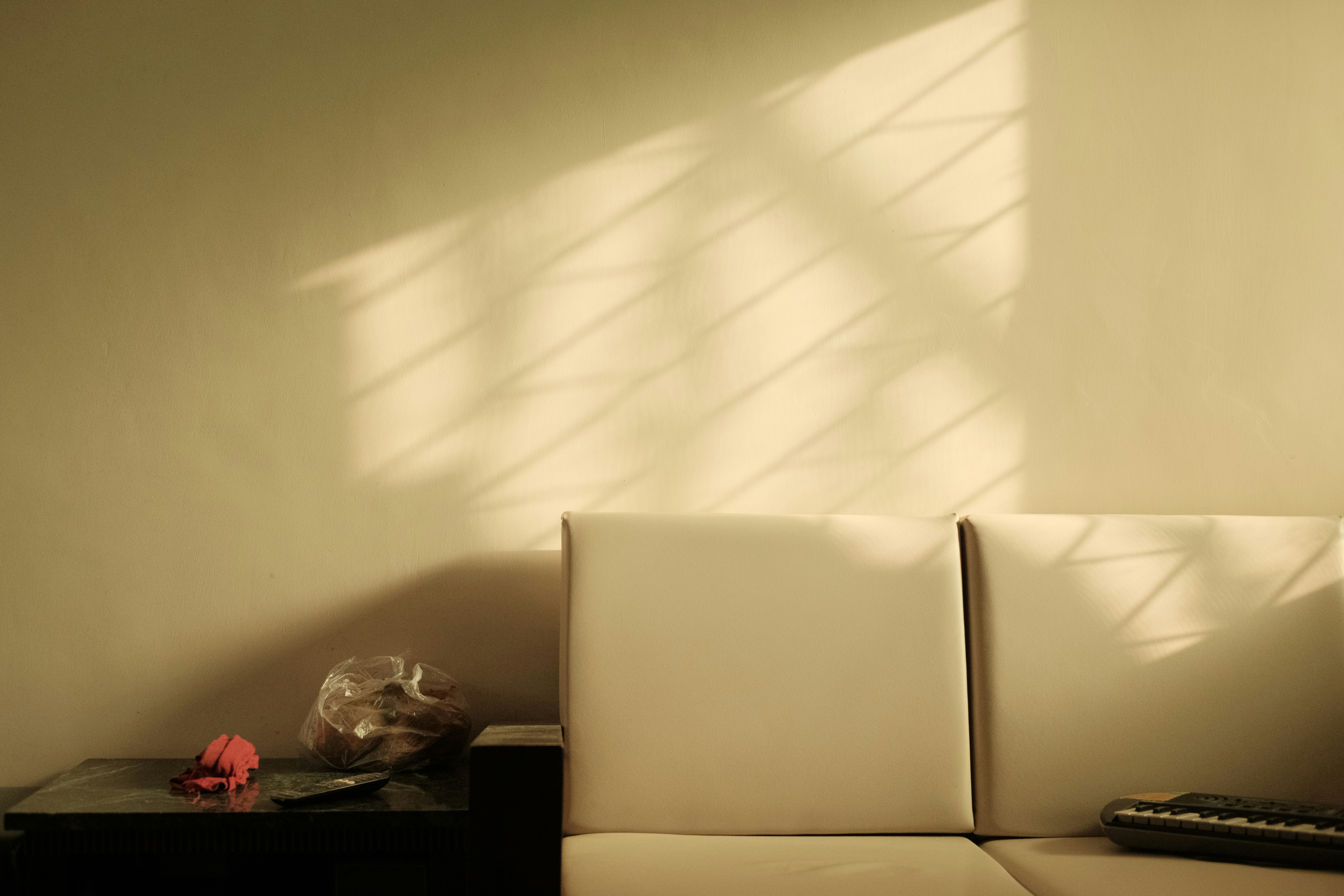 Soft sunlight casts geometric shadows on a neutral-colored couch and side table.