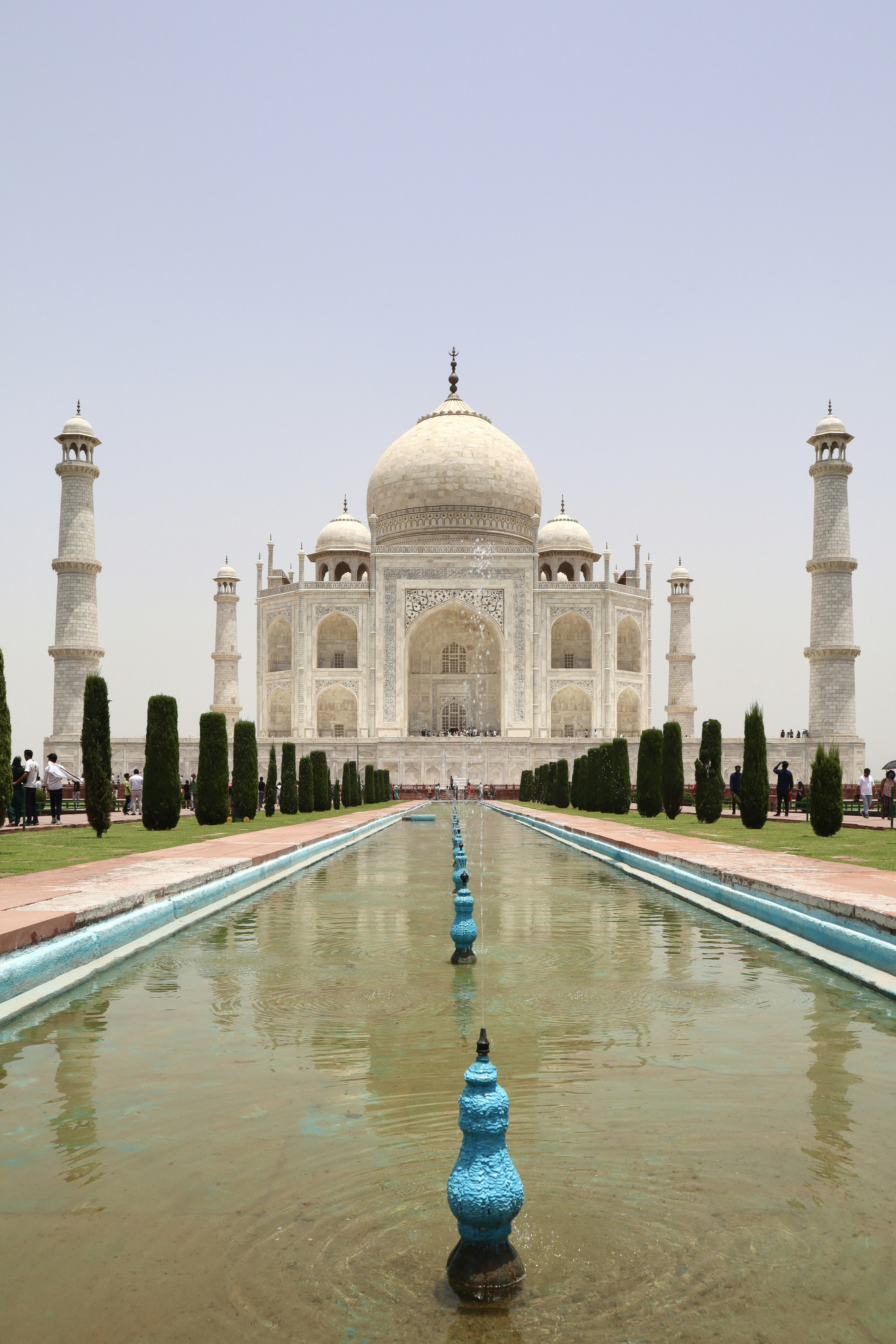 Taj Mahal standing majestically with its reflection mirrored in the central pool, framed by lush gardens.