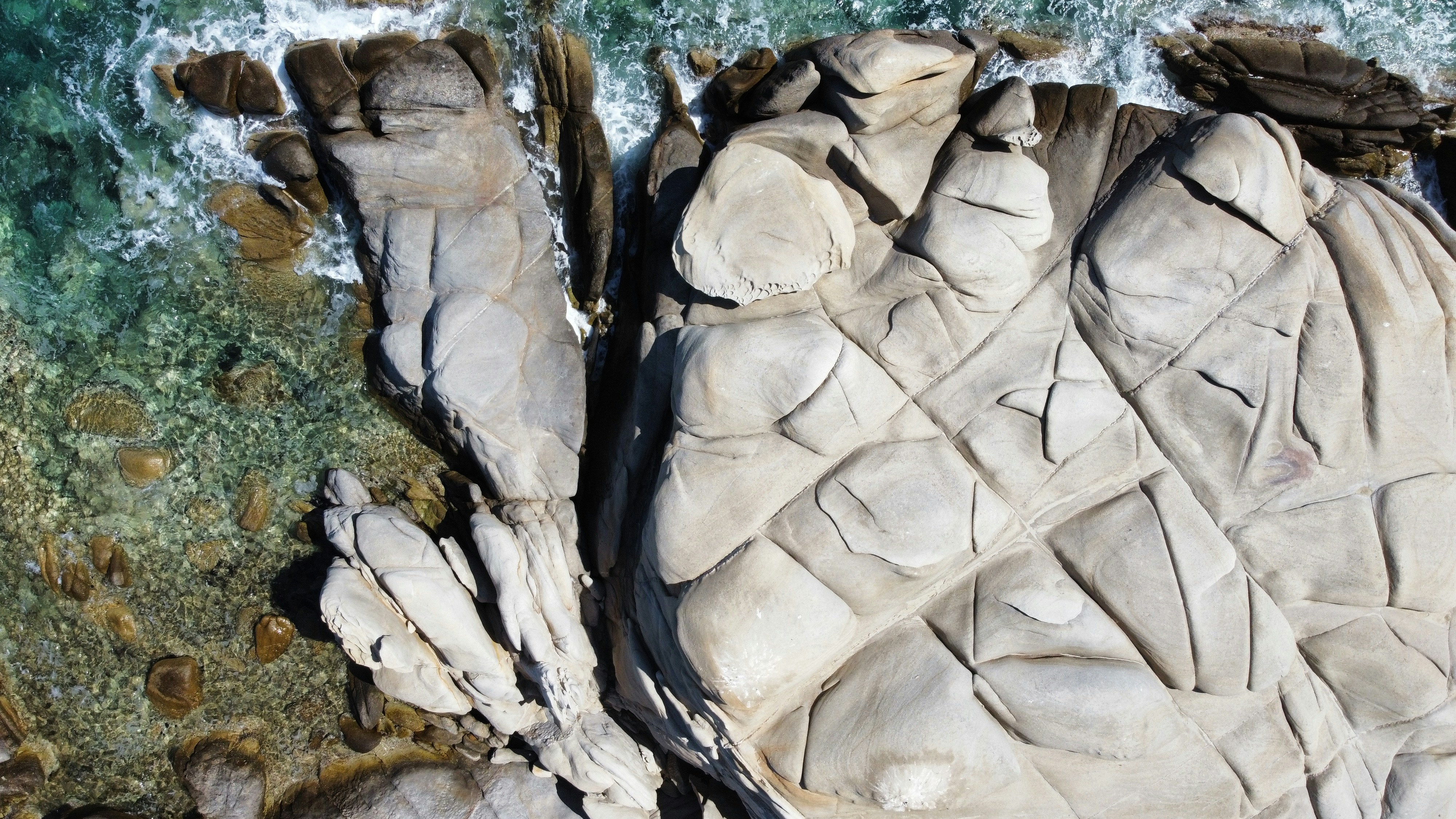 Granite Veins Over Turquoise Tide: An Aerial Portrait of a Rocky Cove