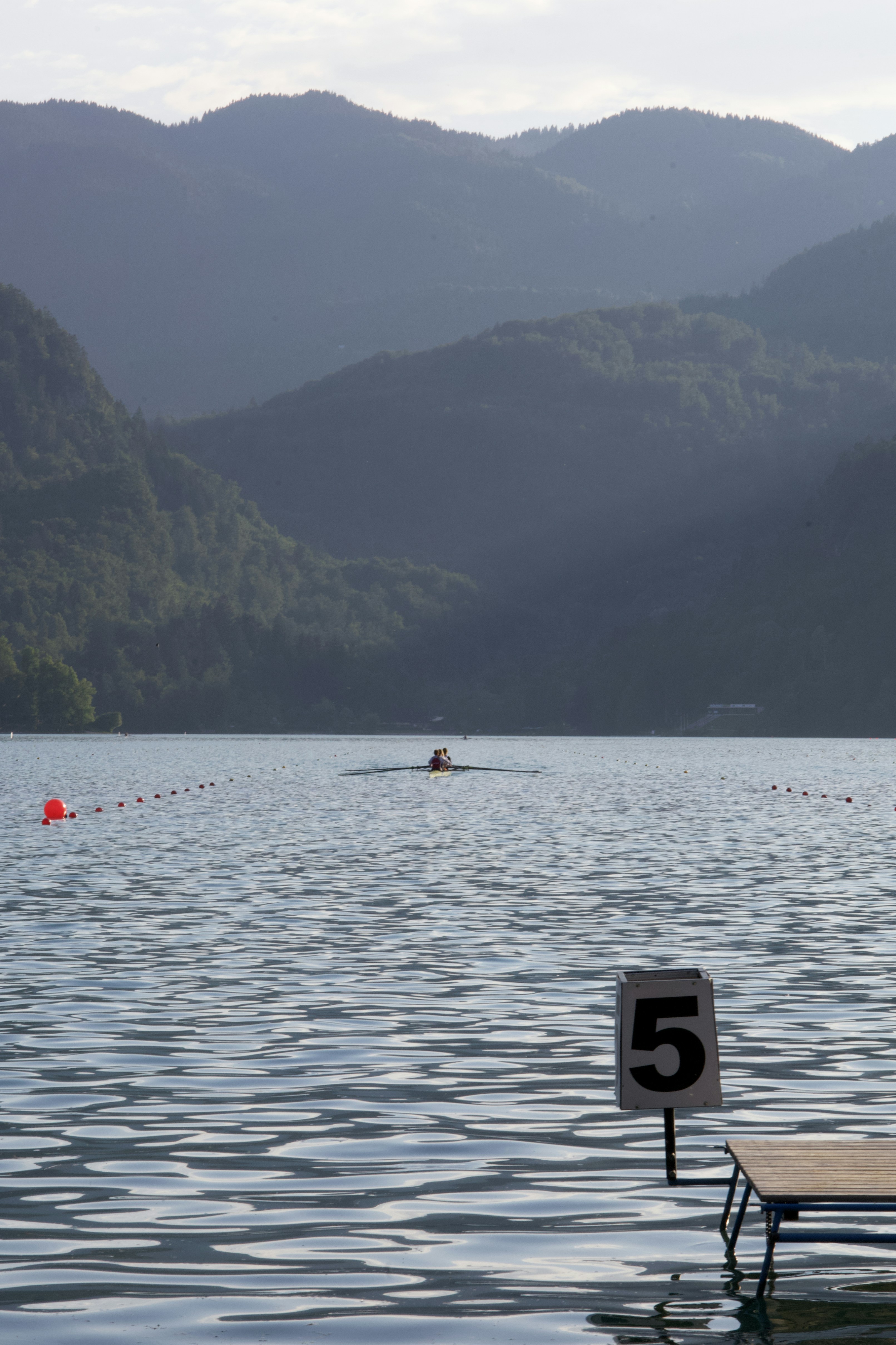 Lone Rowboat Skims a Serene Alpine Lake Under Emerald Peaks