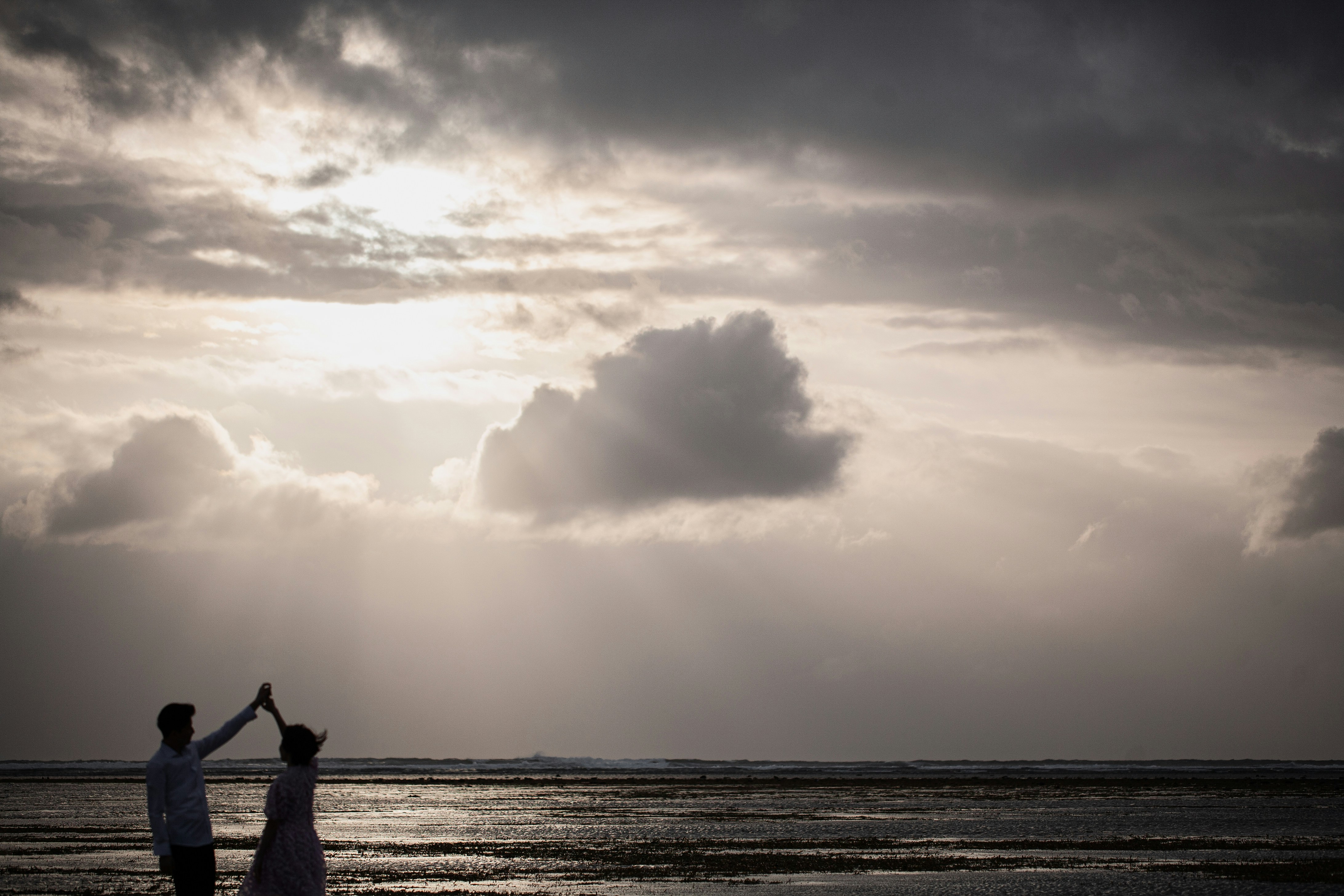 Sunset Waltz on a Quiet Shore: Silhouetted Lovers Beneath Narrow Sunbeams