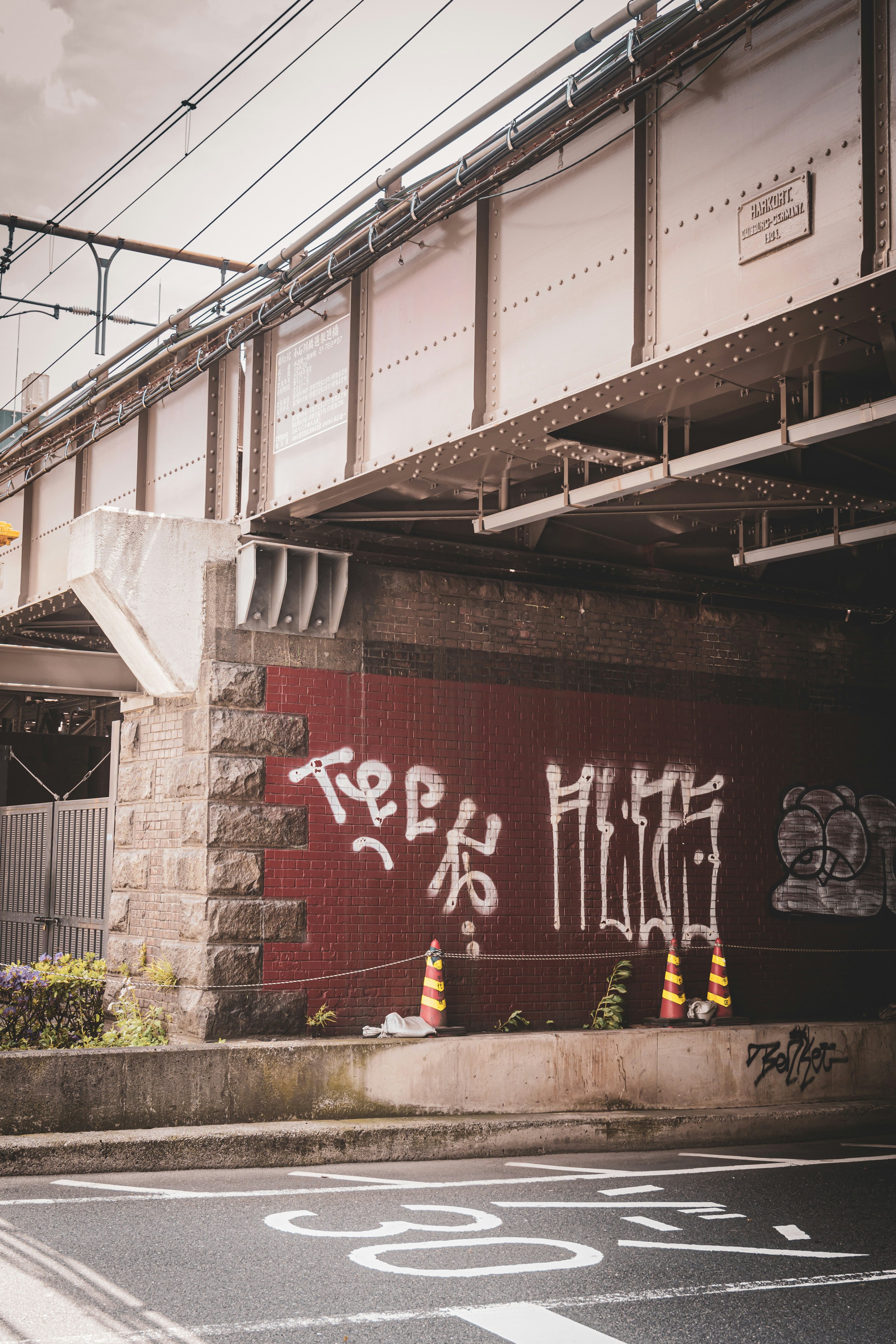 Underpass Graffiti: Red Brick, Orange Cones, and a Quiet Street