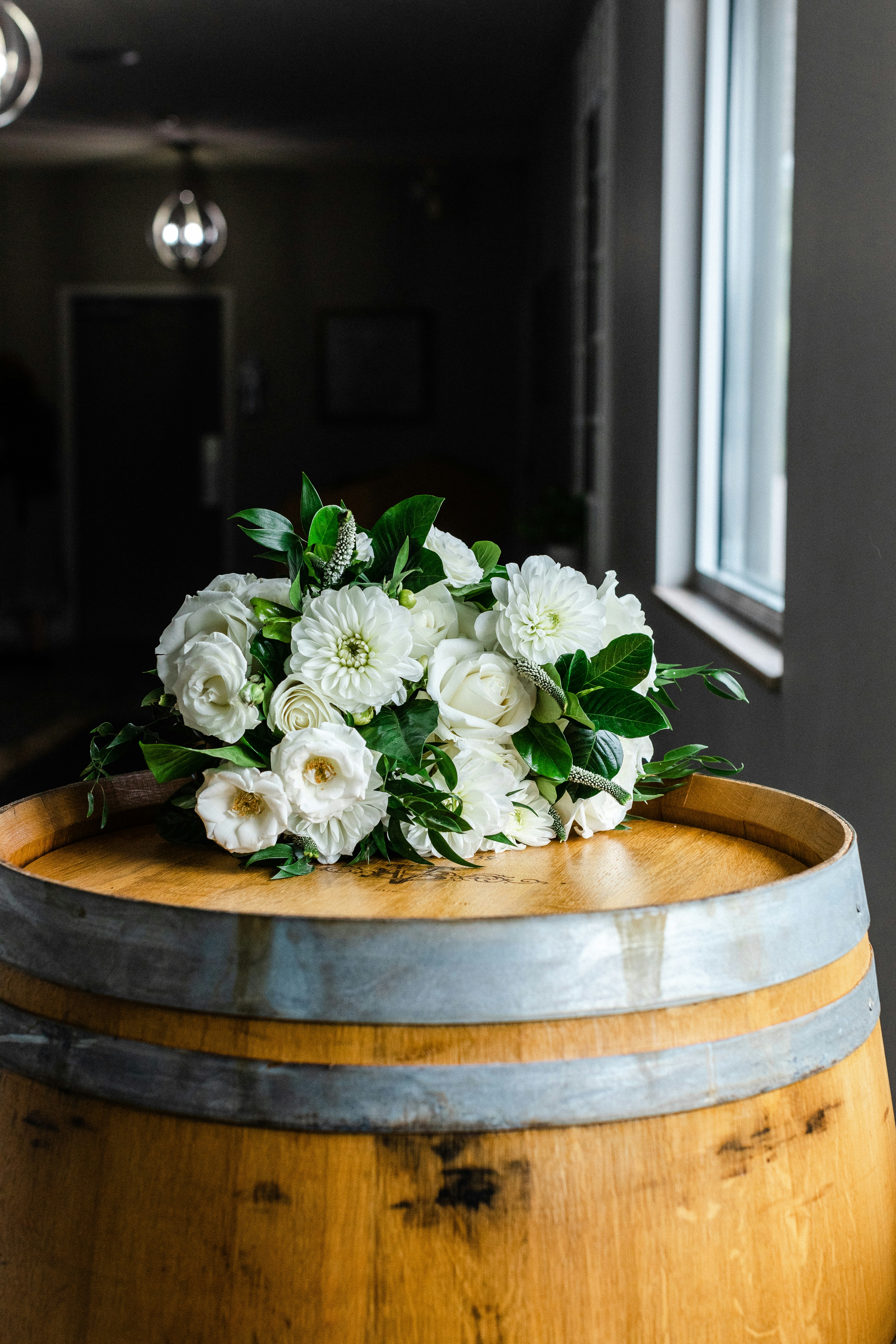 White Bouquet on a Barrel: Quiet Elegance in a Dim Hallway