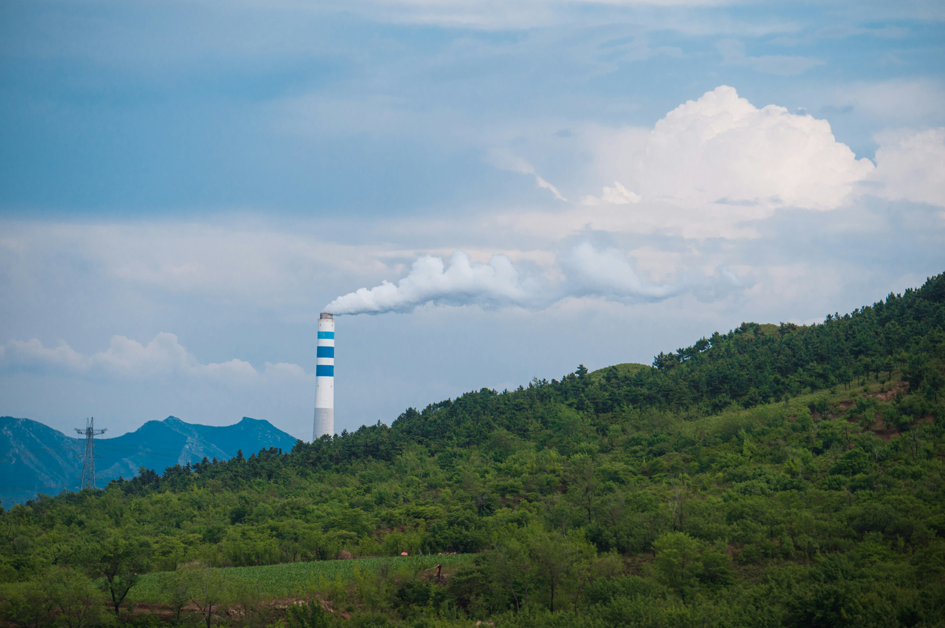 A smokestack emits from the top of a hill photo – Free Cloud Image on ...