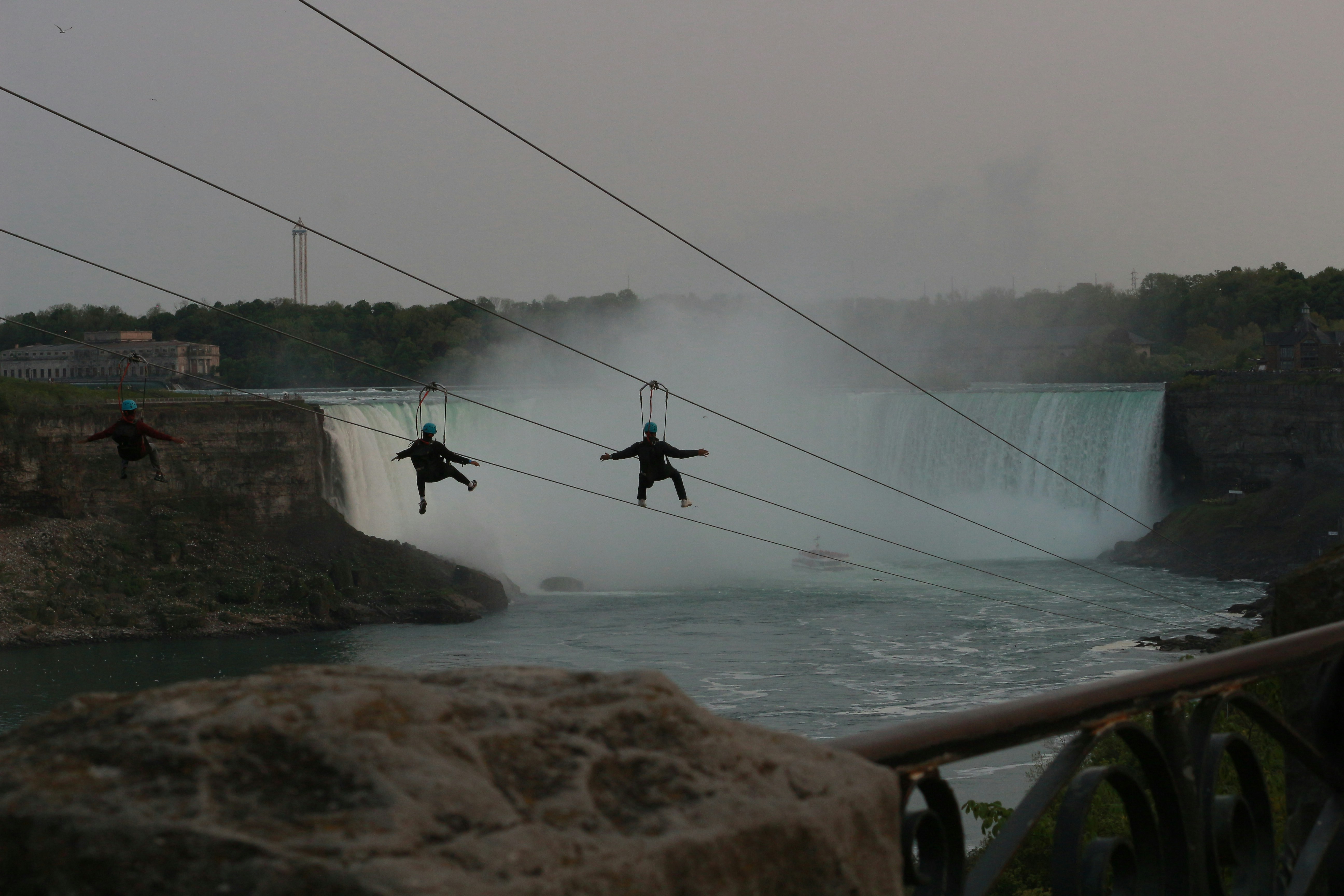 A group of people hanging from wires above a river photo – Free Niagara ...