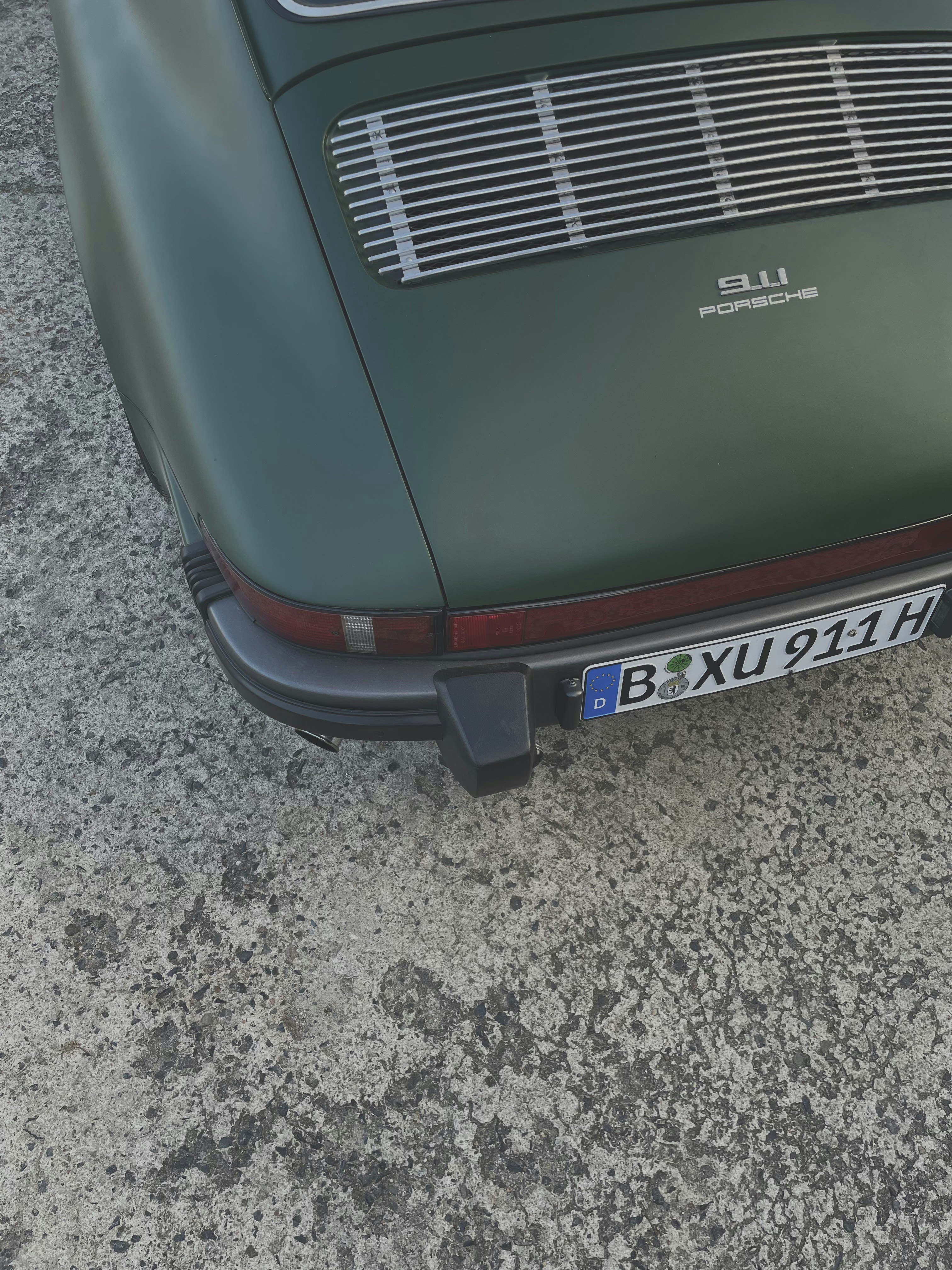 Matte-Green Porsche 911: A Quiet Rear View on Weathered Asphalt