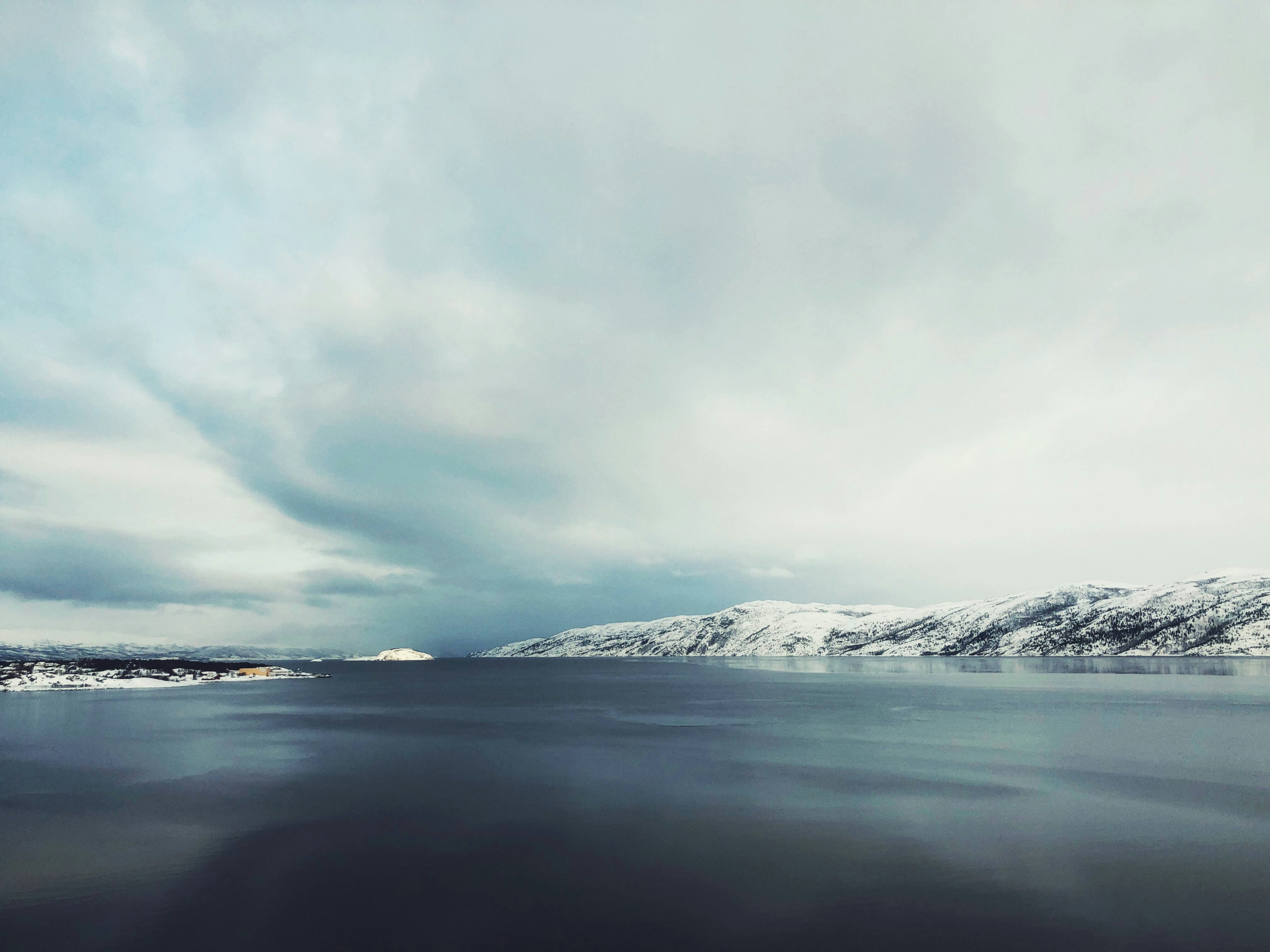Stunning stillness of the Norwegian north. | a large body of water surrounded by snow covered mountains