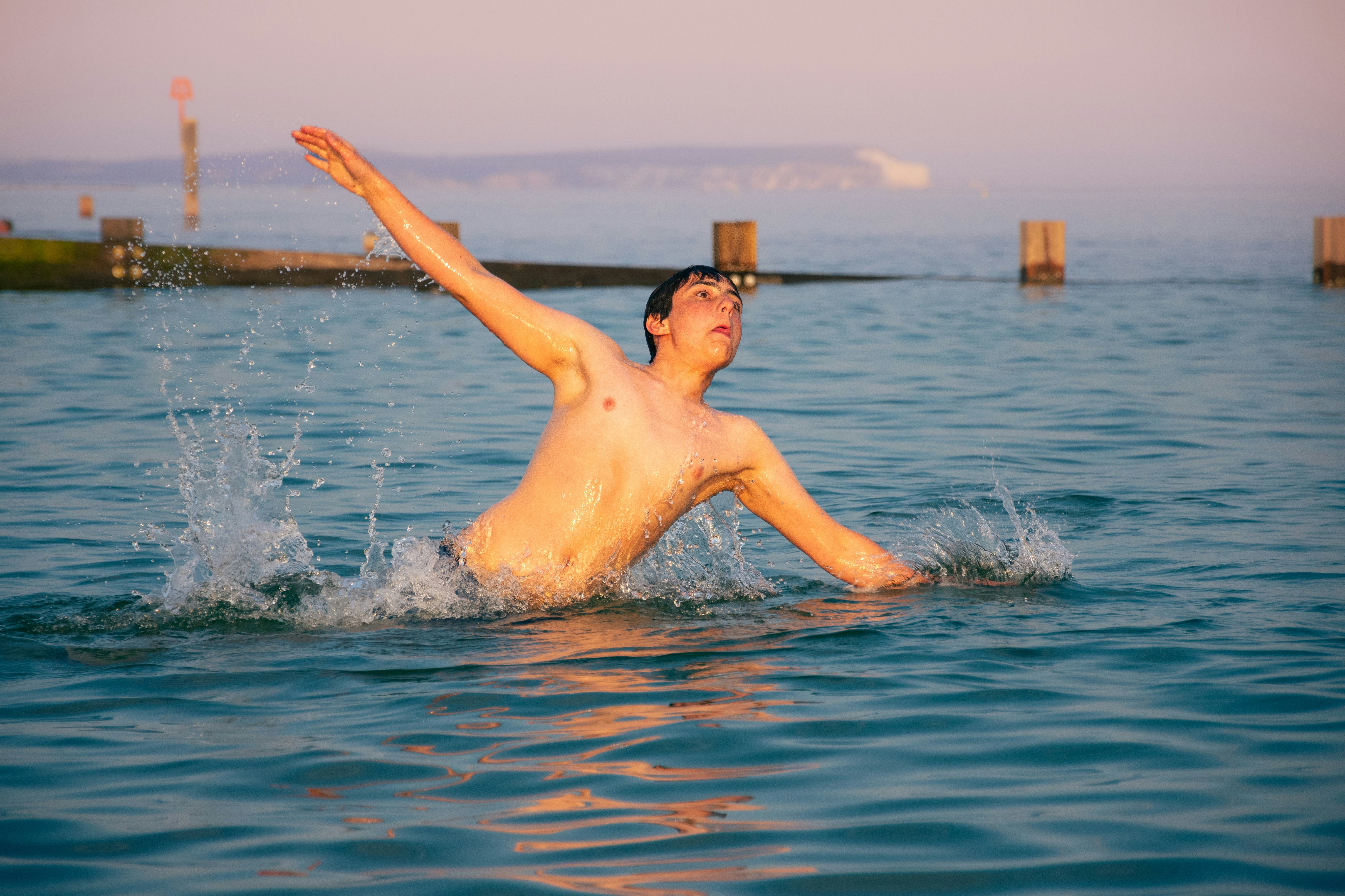 Splash Arc in Sunlit Sea: A Bare-Chested Leap Through Blue Calm