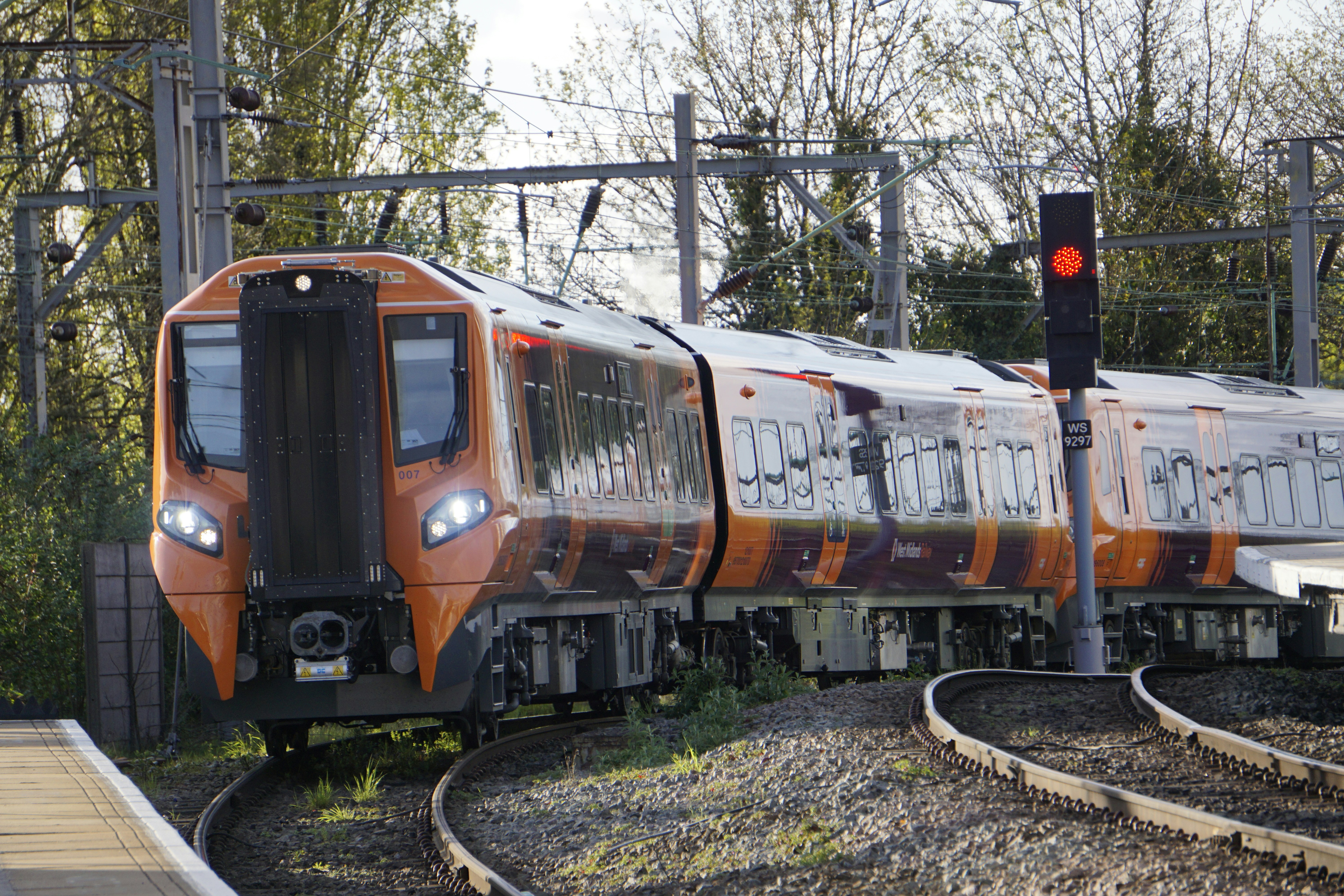 Un train orange et blanc circulant sur les voies ferrées photo – Image ...