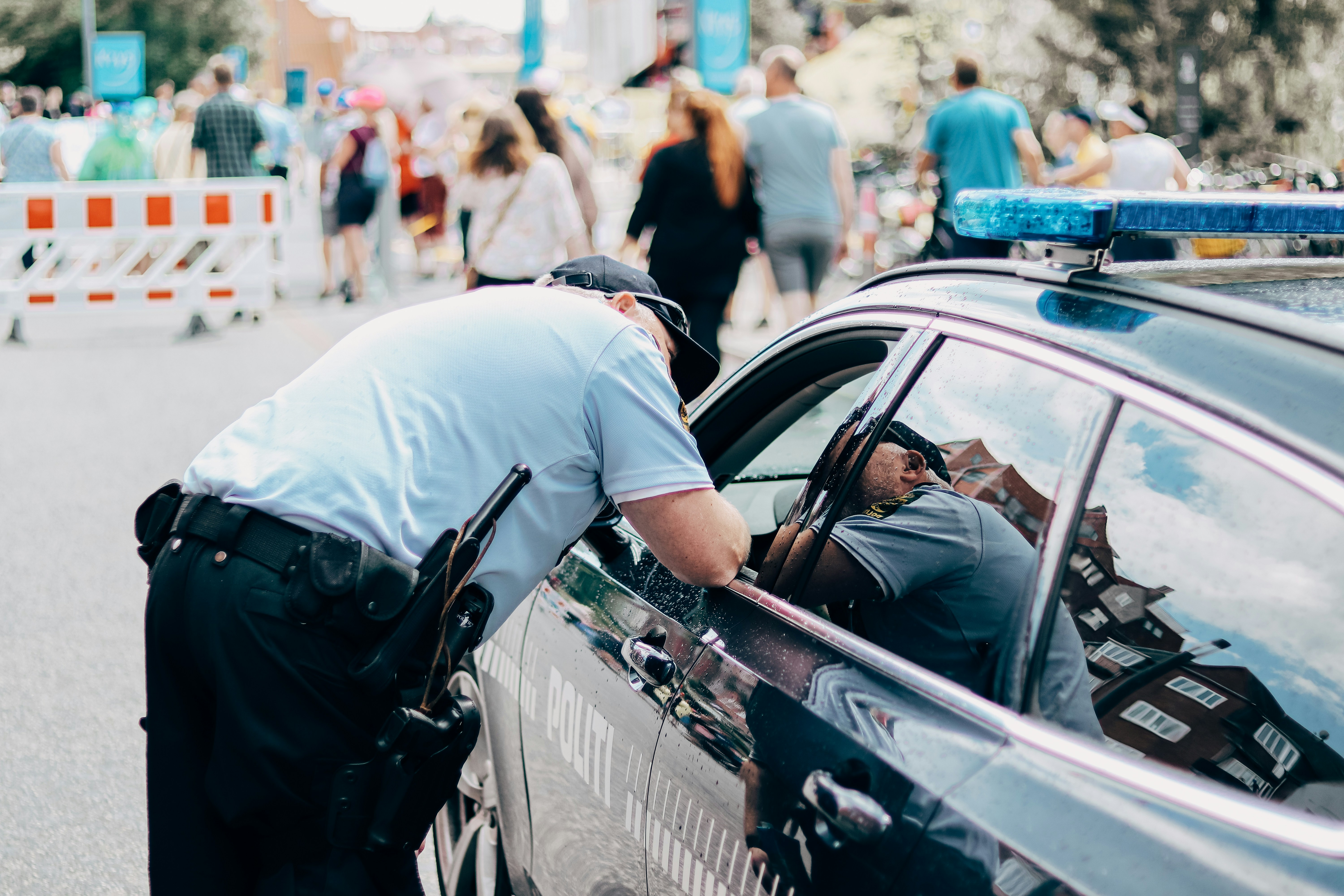 A police officer leaning into a police car photo – Free Car Image on ...