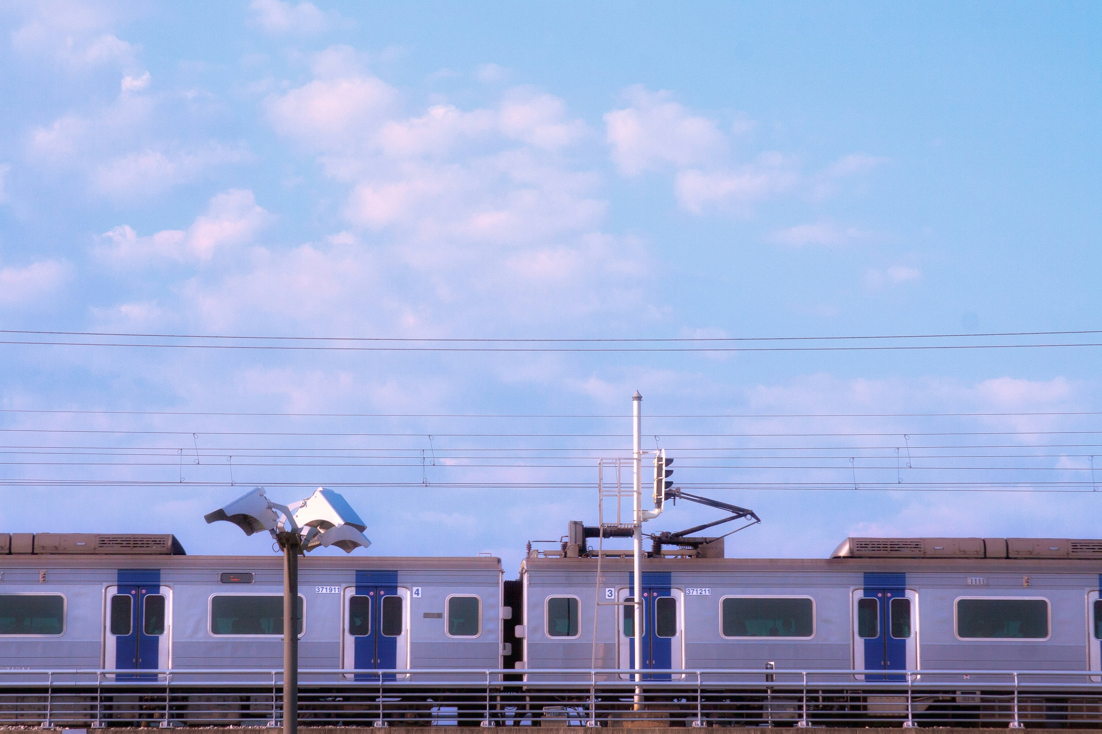 Pastel Sky over Blue Carriages: Quiet Transit on Elevated Rails
