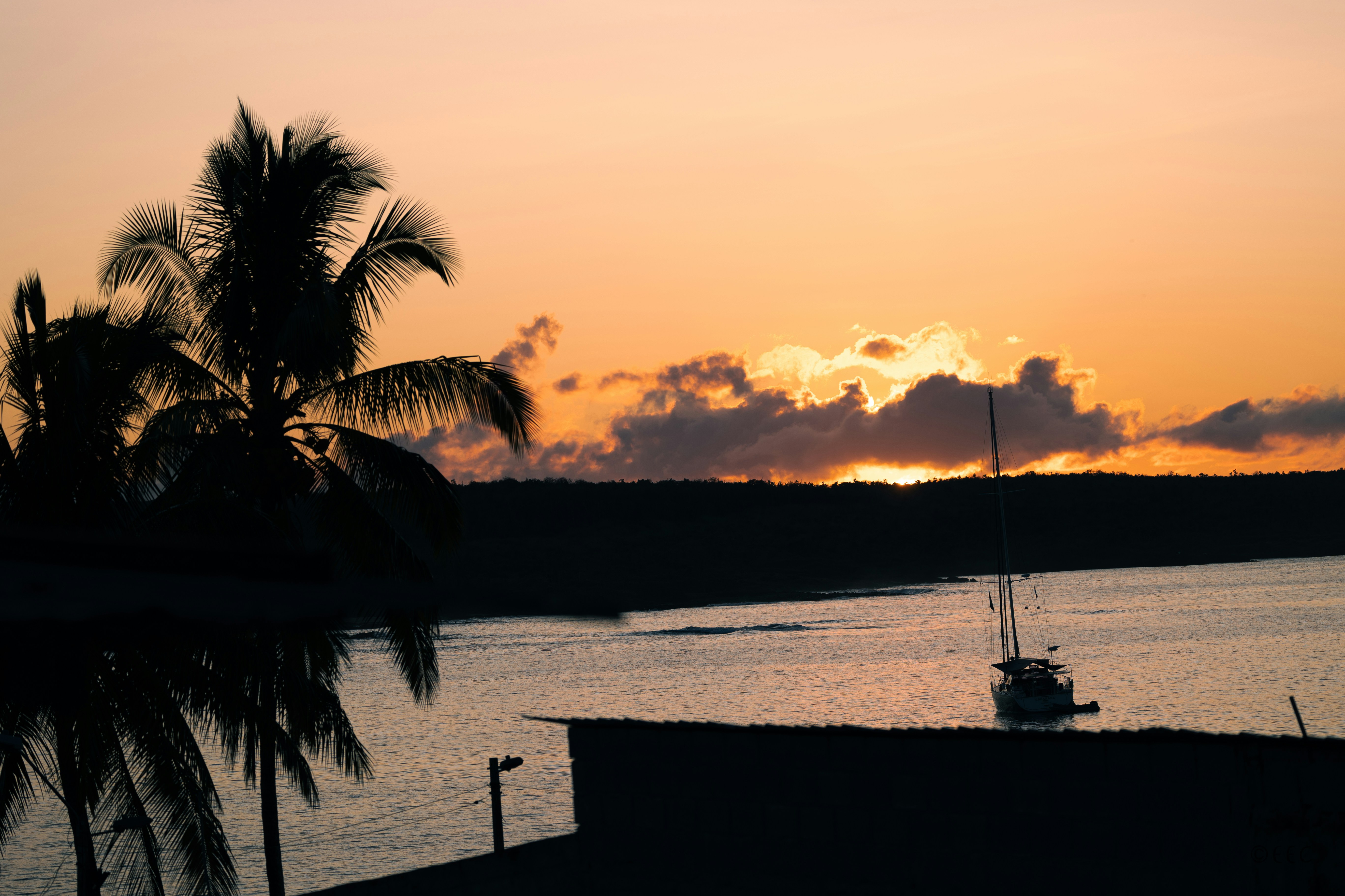 Ember Horizon: Sailboat Silhouette Over a Quiet Channel at Sunset