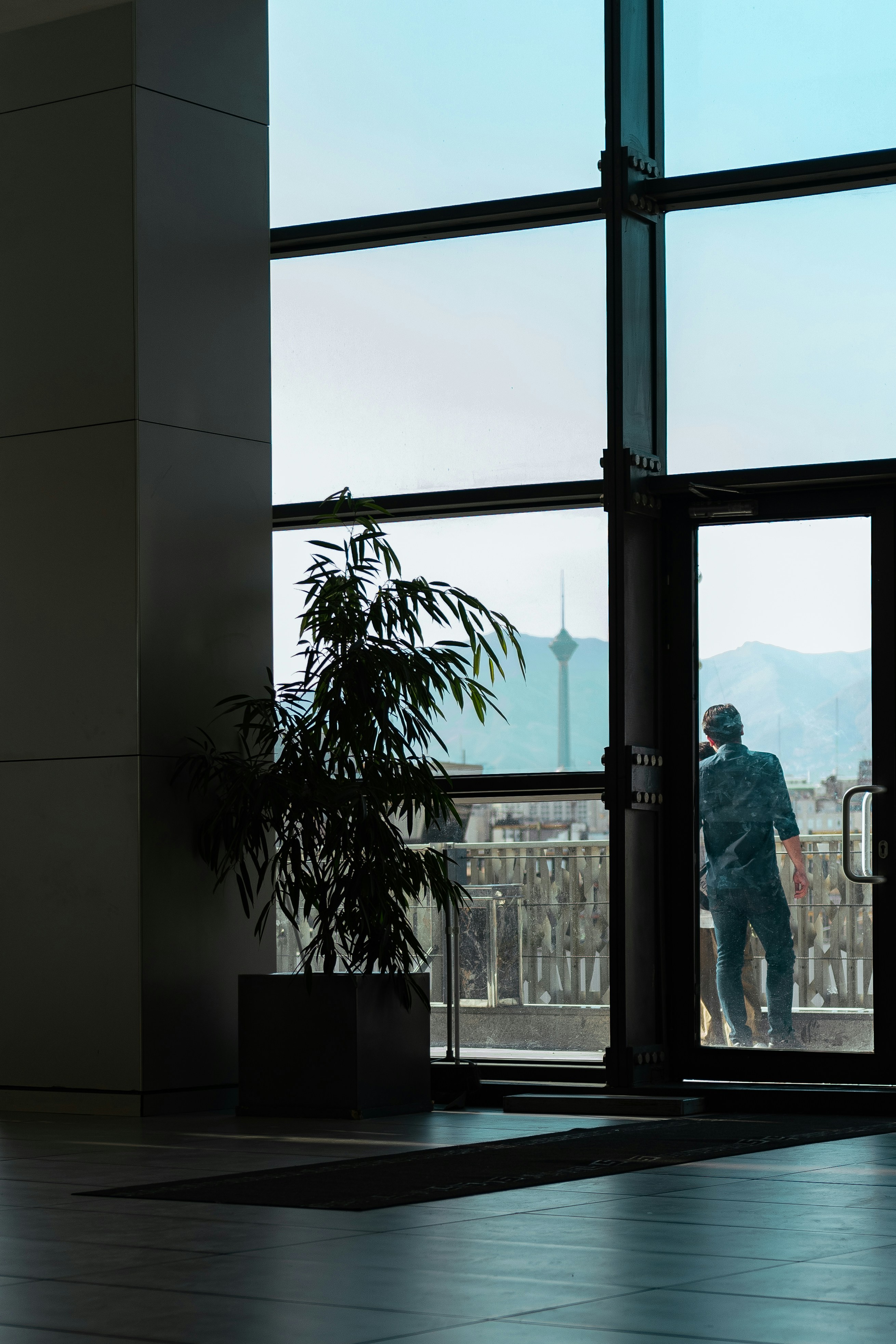 Glass Threshold: A Lone Figure Framing the City Beyond