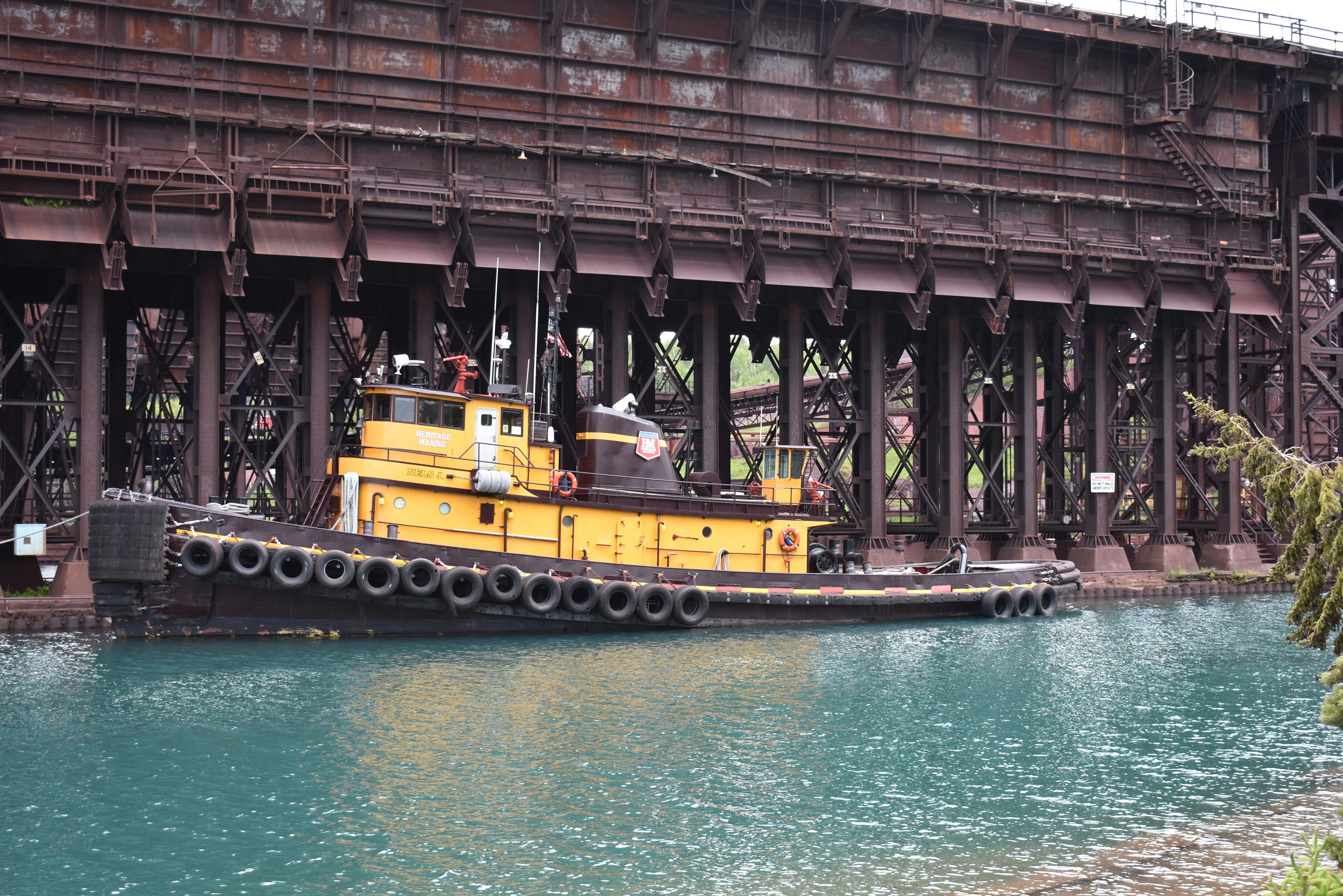Yellow Tug against a Steel Cascade: A Riverside Work Scene