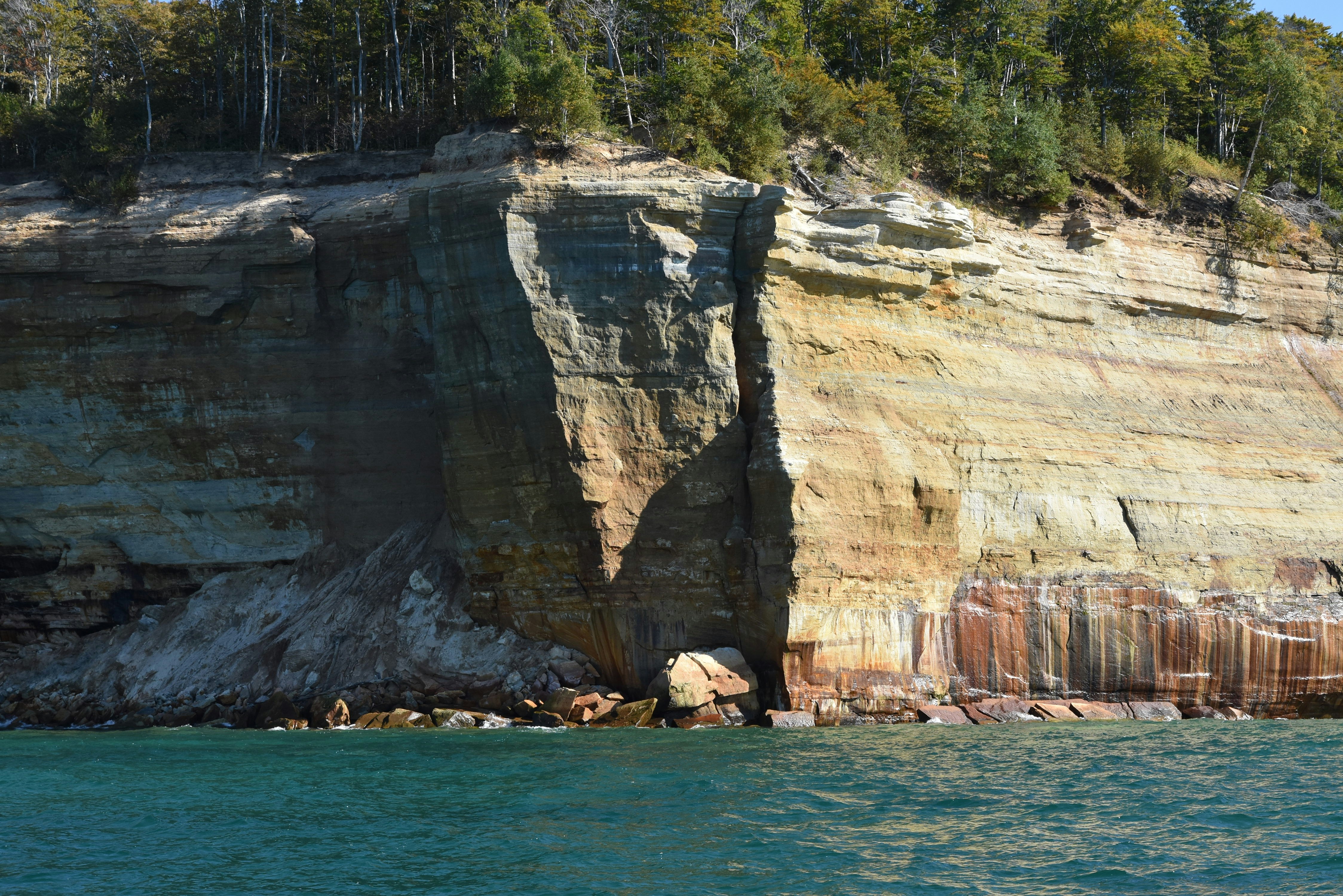 A large cliff on the edge of a body of water photo – Free Cliff Image ...