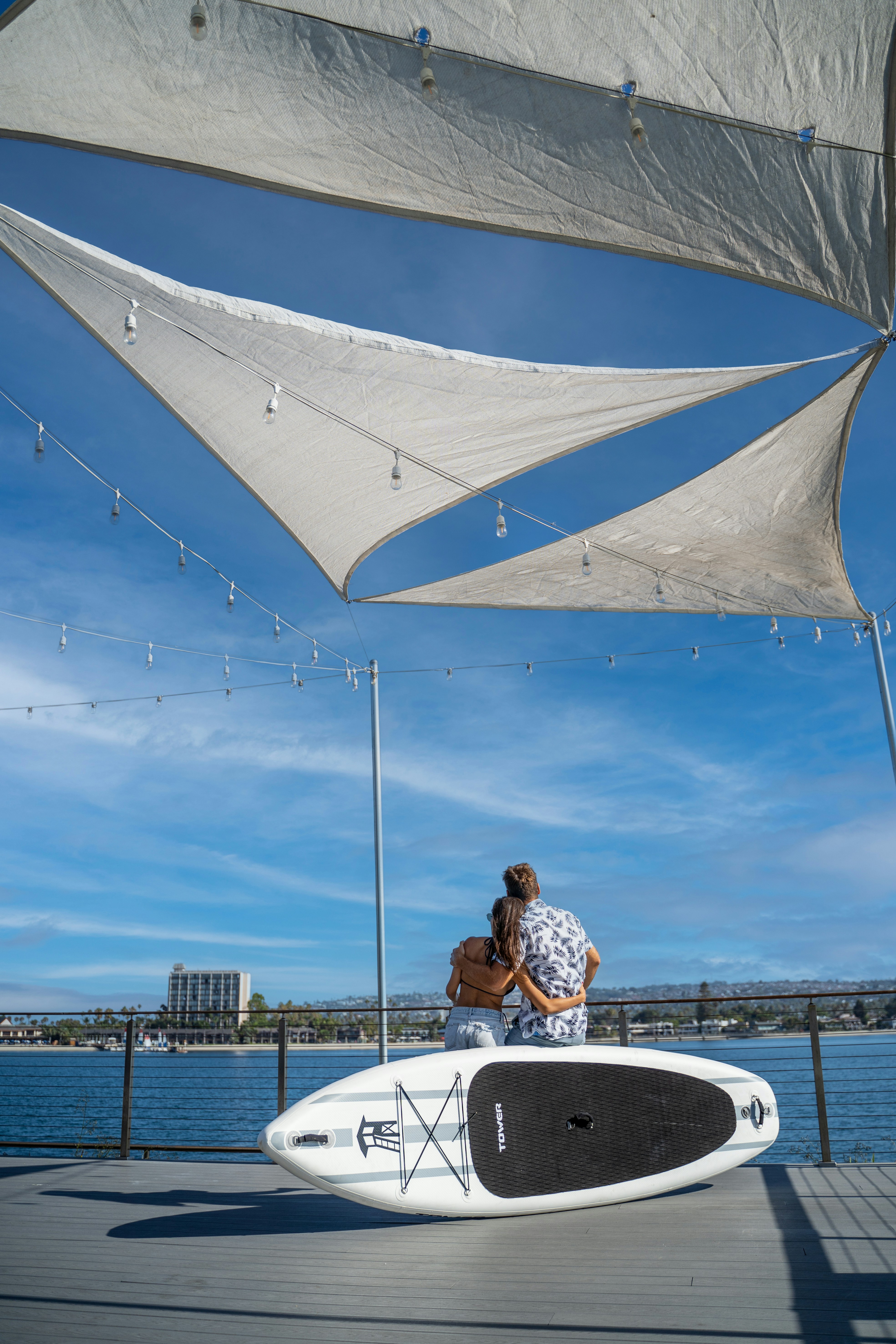 A man sitting on top of a surfboard under a sail photo – Free Woman ...