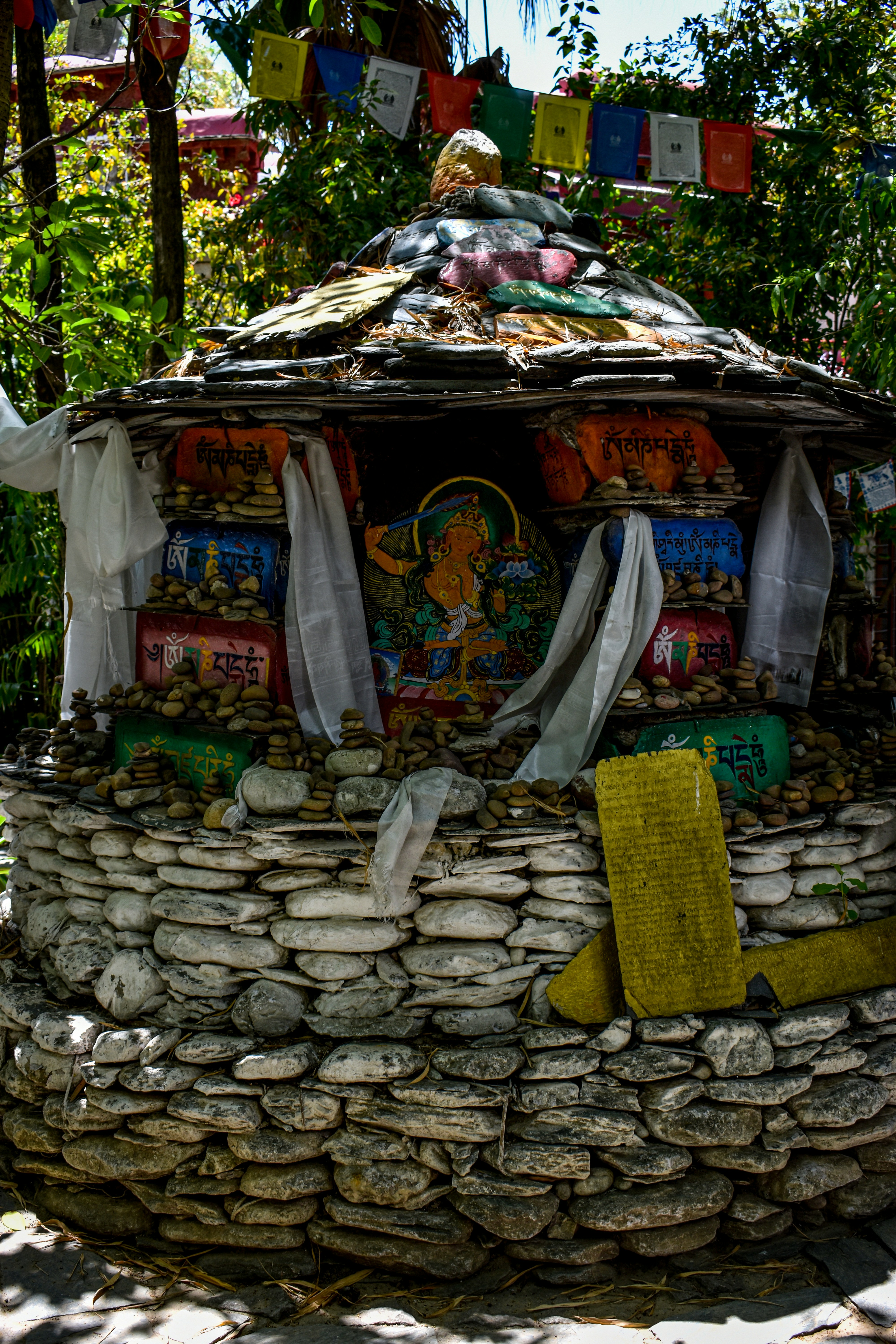 Painted Deity in a Stone Ring Framed by Colorful Prayer Flags