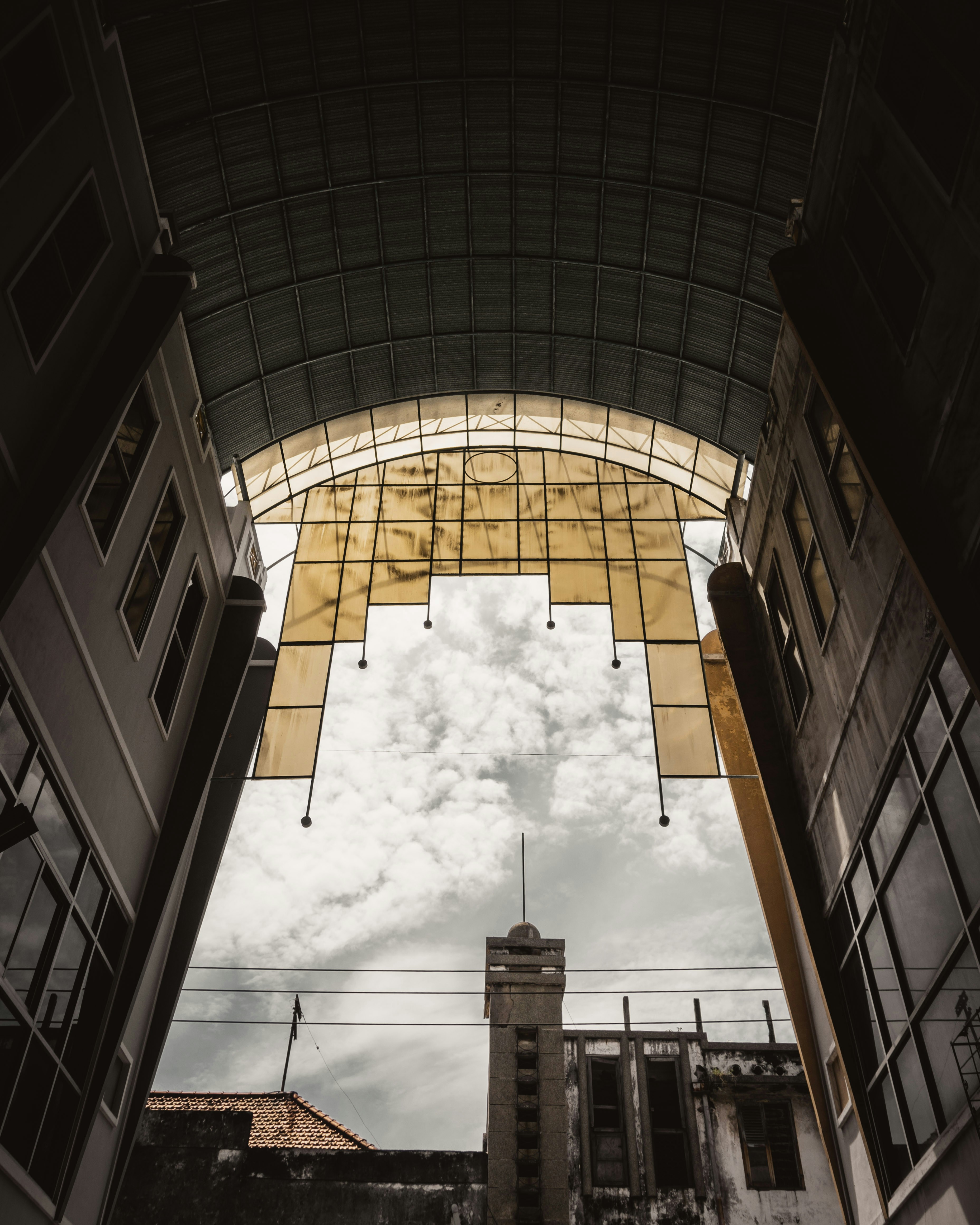 Archway to the Sky: Amber Glass Framing a Cloudy Break in a Dim Atrium